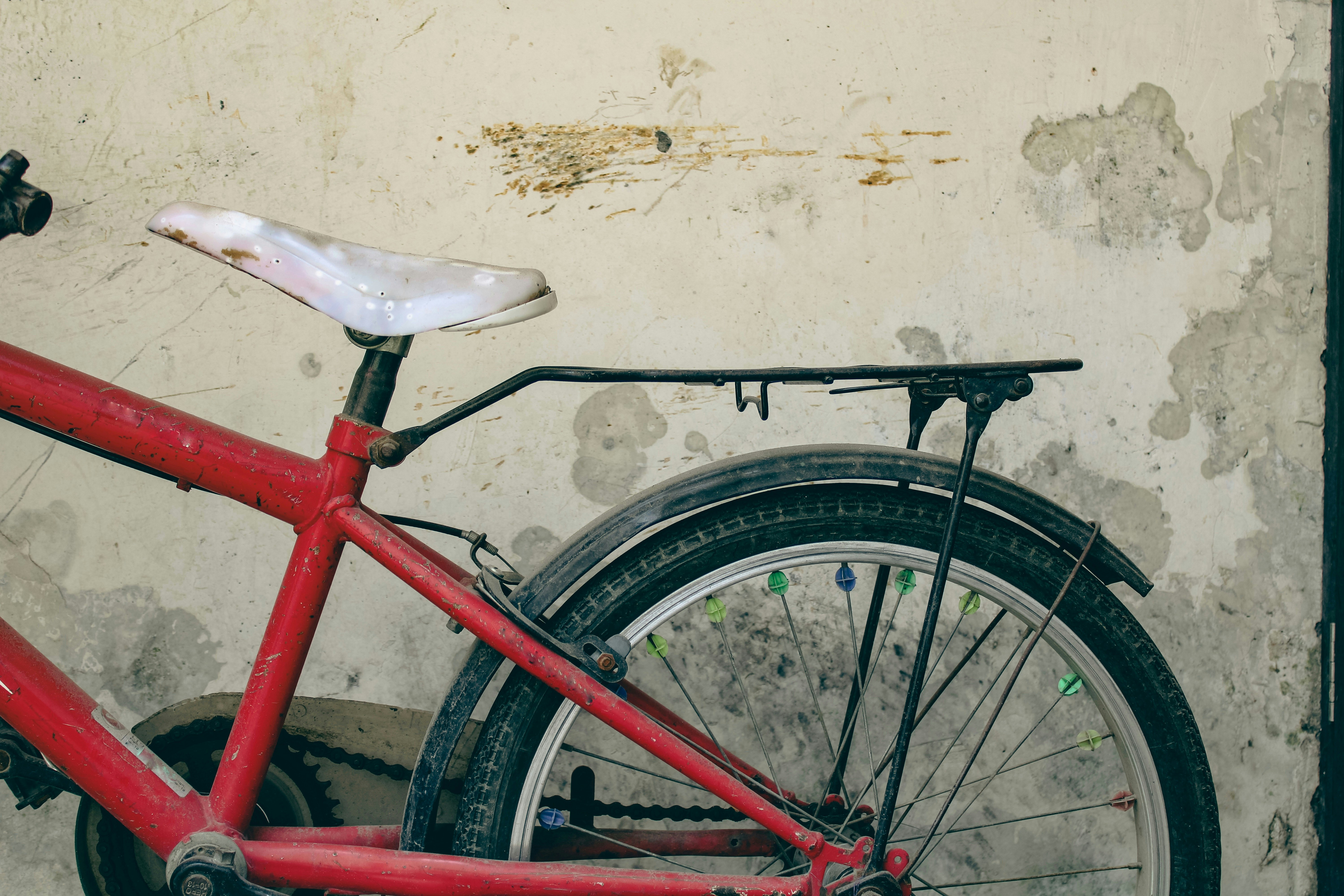 Red Bicycle Frame Touches a Weathered Wall
