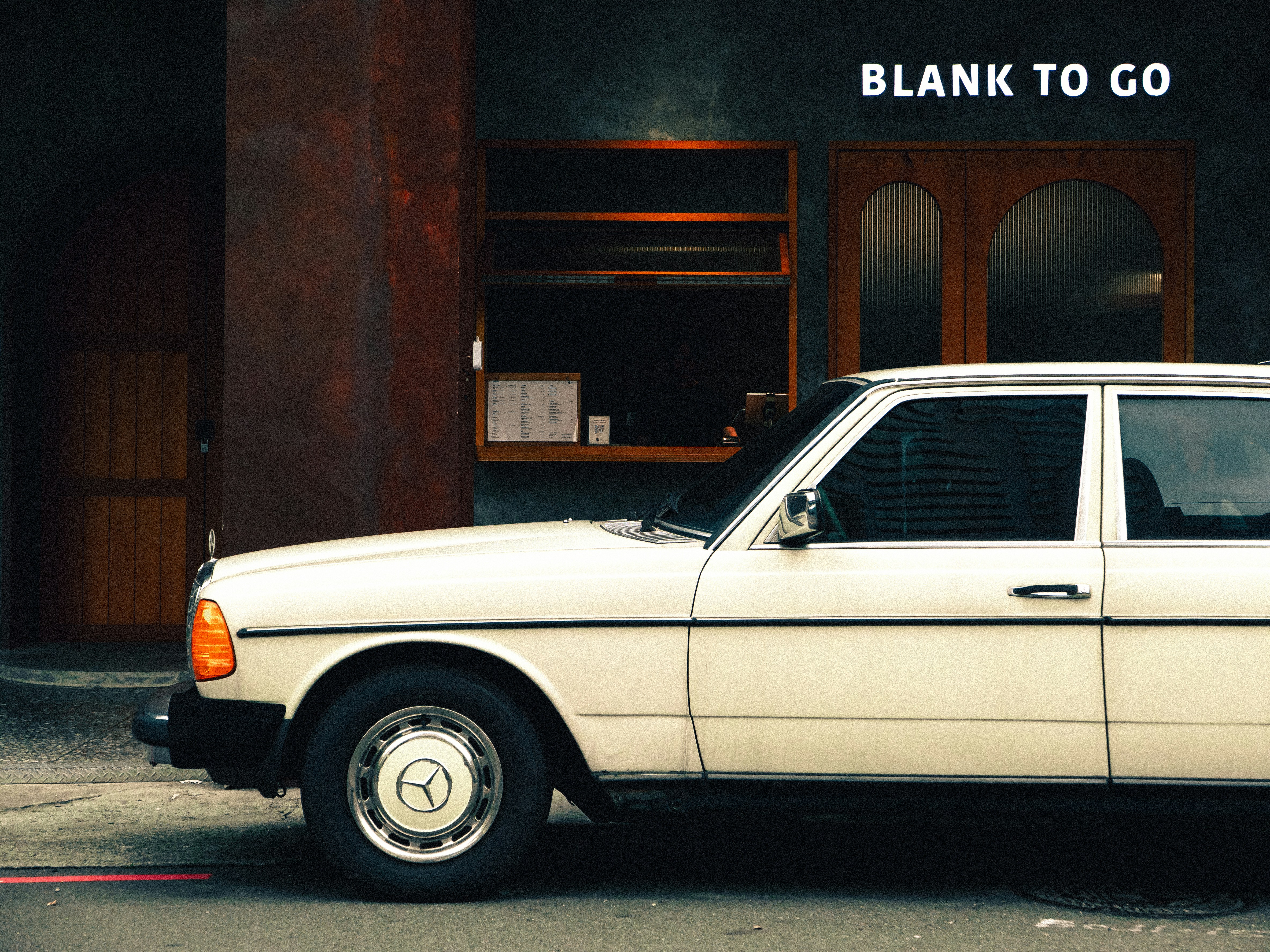 Mercedes on a Quiet Street: A Retro Sedan in Front of a Night-Warmed Facade