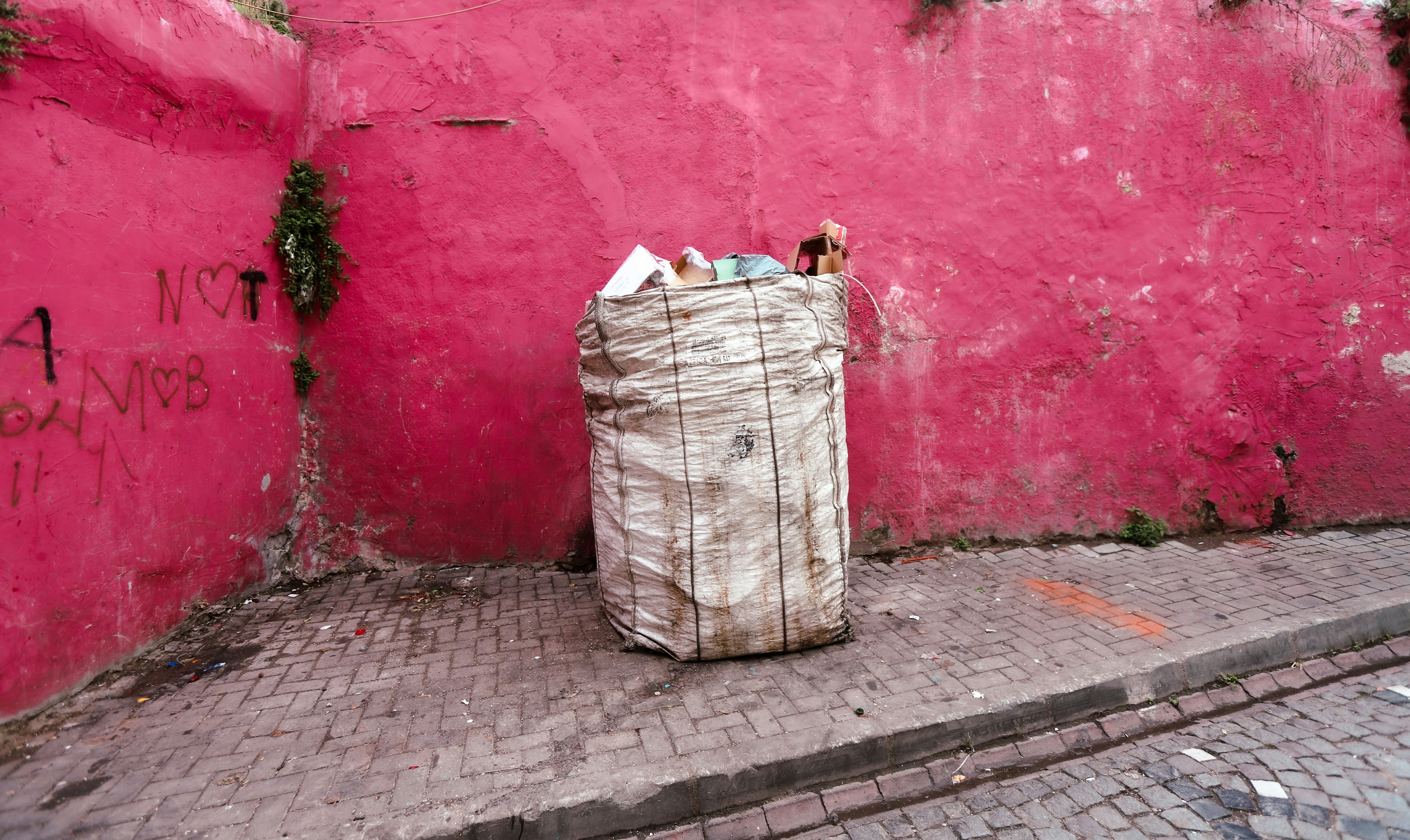 Crimson Wall and a Lonely Receptacle on a Cobblestone Street