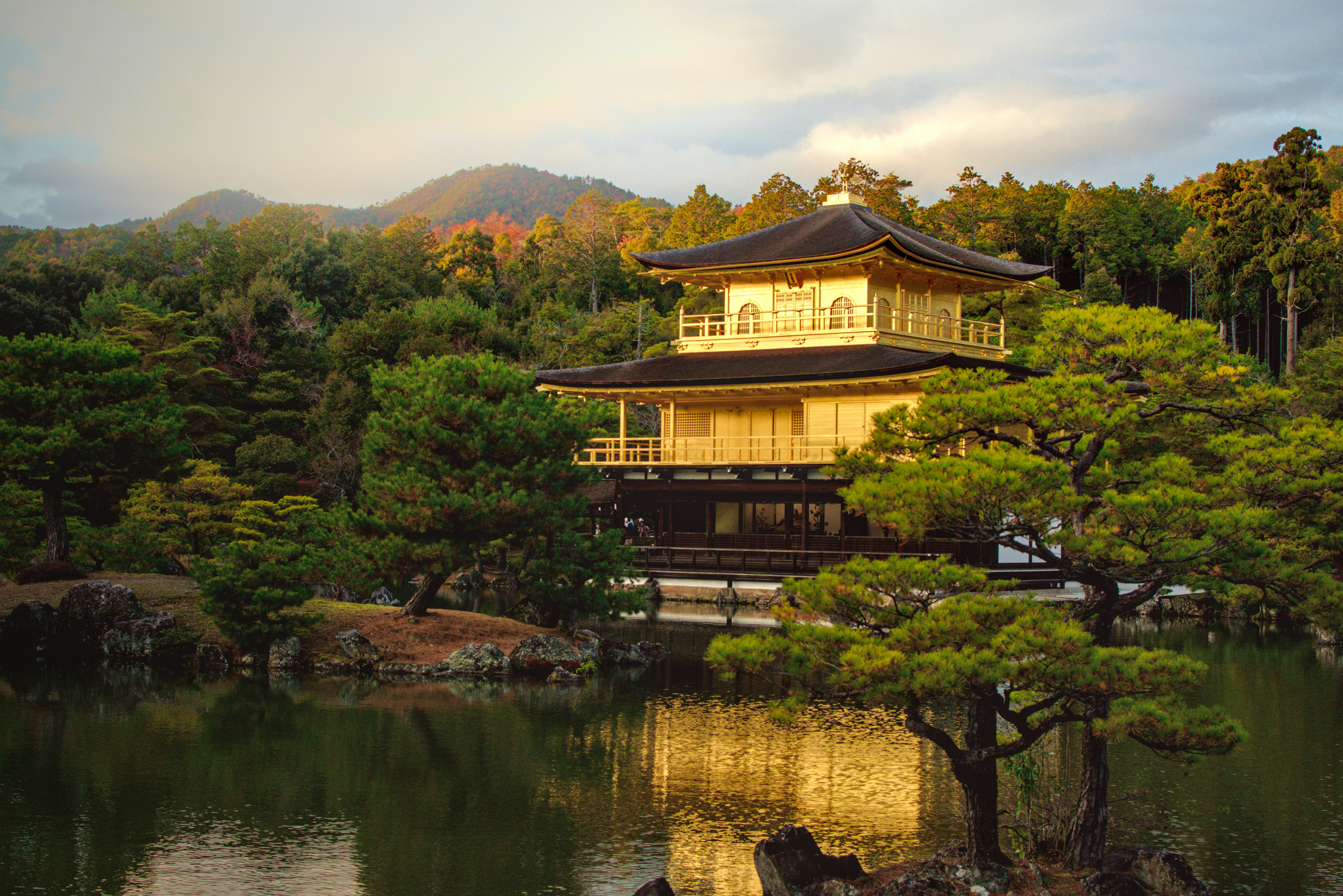 Golden temple reflected in calm water surrounded by trees