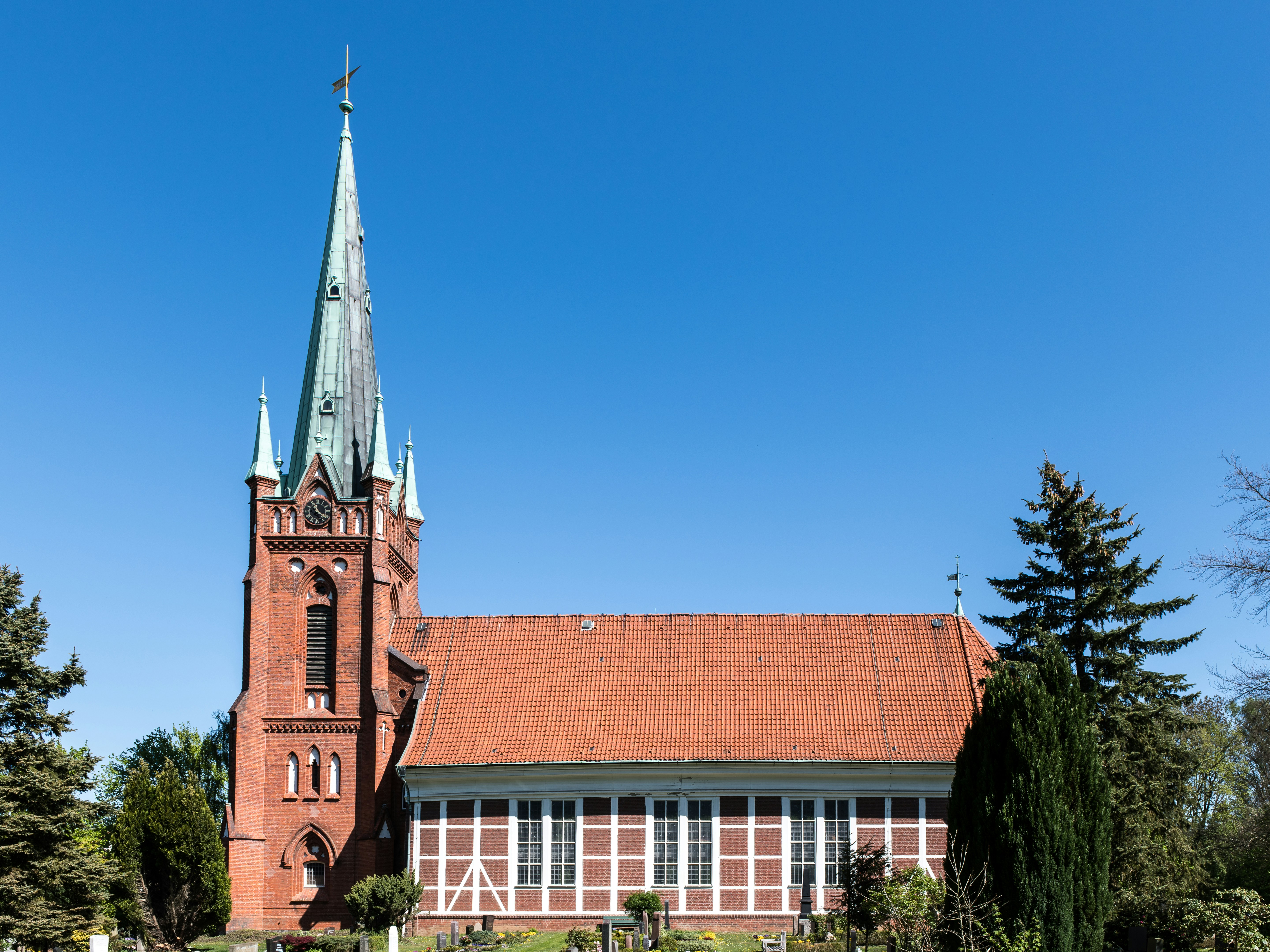 Red Brick Church with Turreted Spire Under a Clear Blue Sky