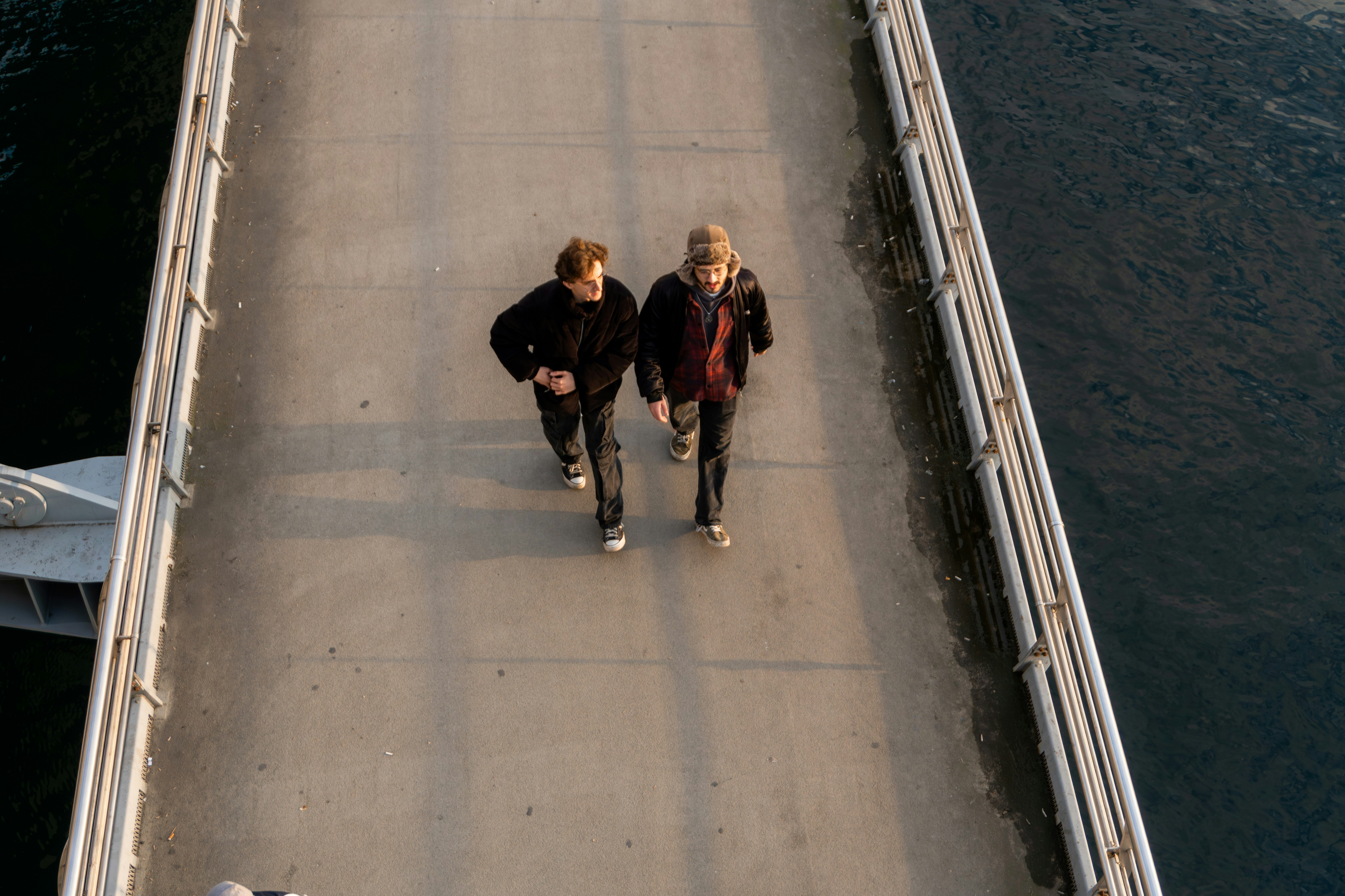 Overhead Stroll: Two Friends Crossing a Quiet Bridge