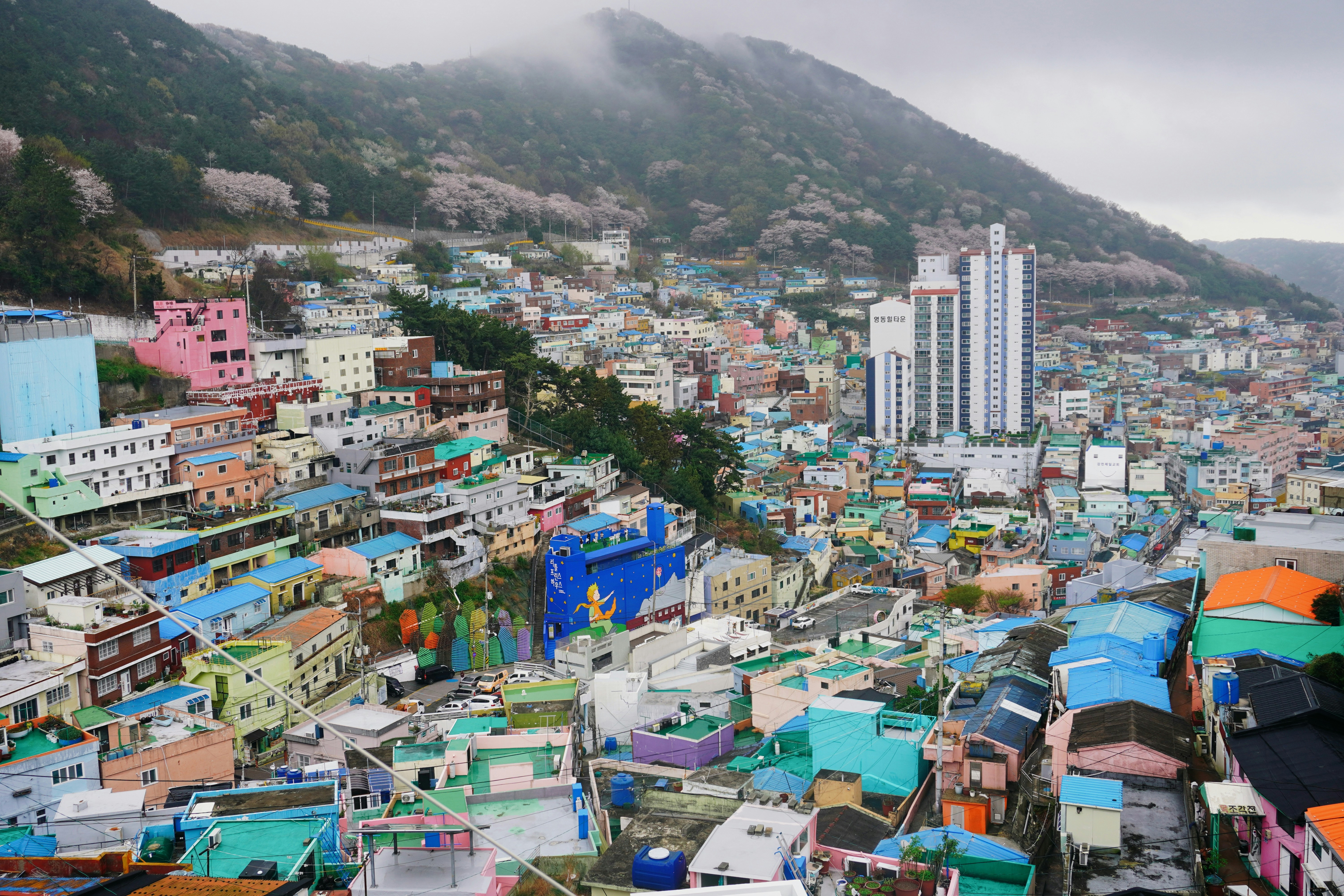 Colorful hillside town with terraced rooftops beneath a misty ridge
