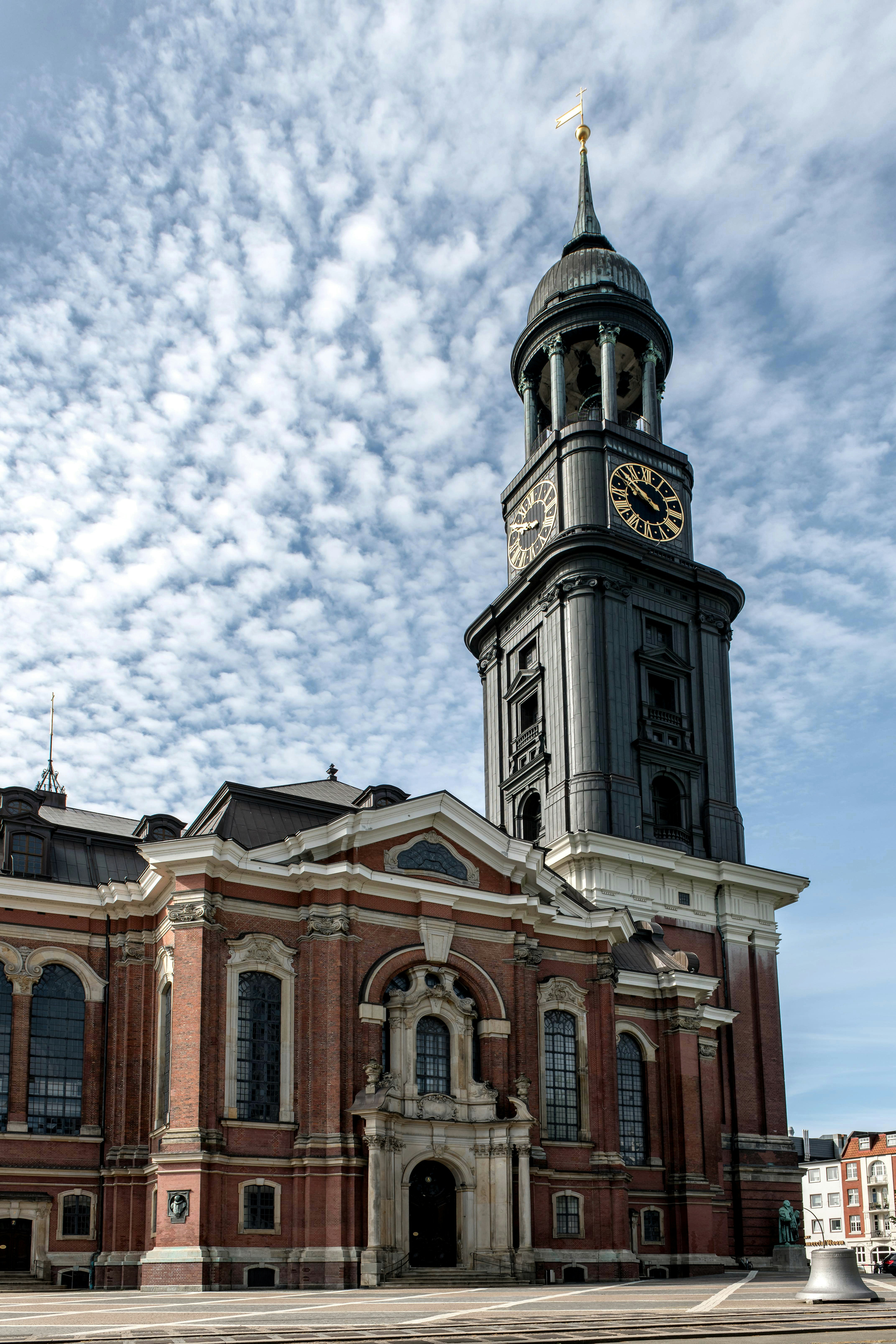 Clocktower over a grand brick façade in a sunlit city square