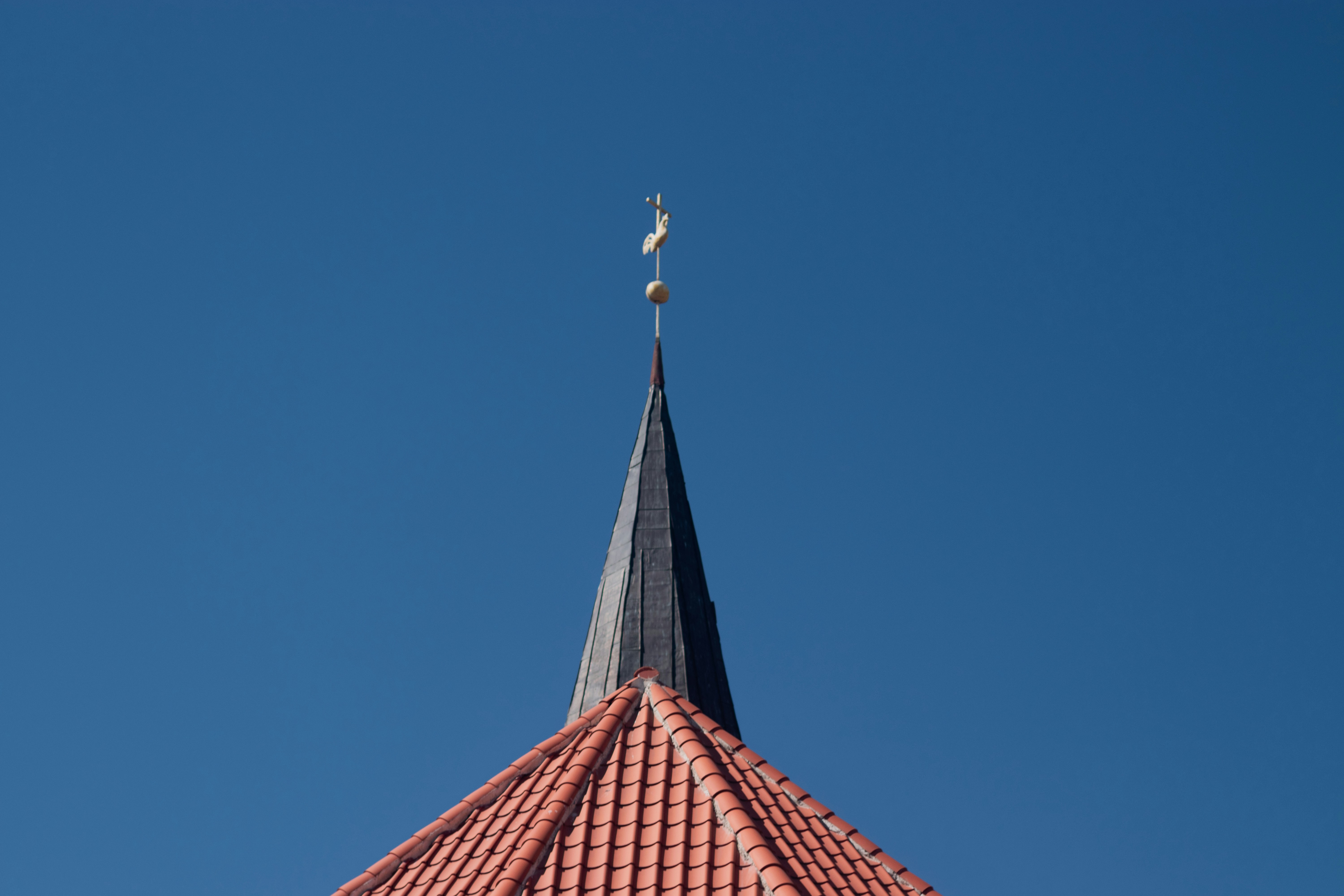 Spire Silhouette Rising Over Red Tile Roof