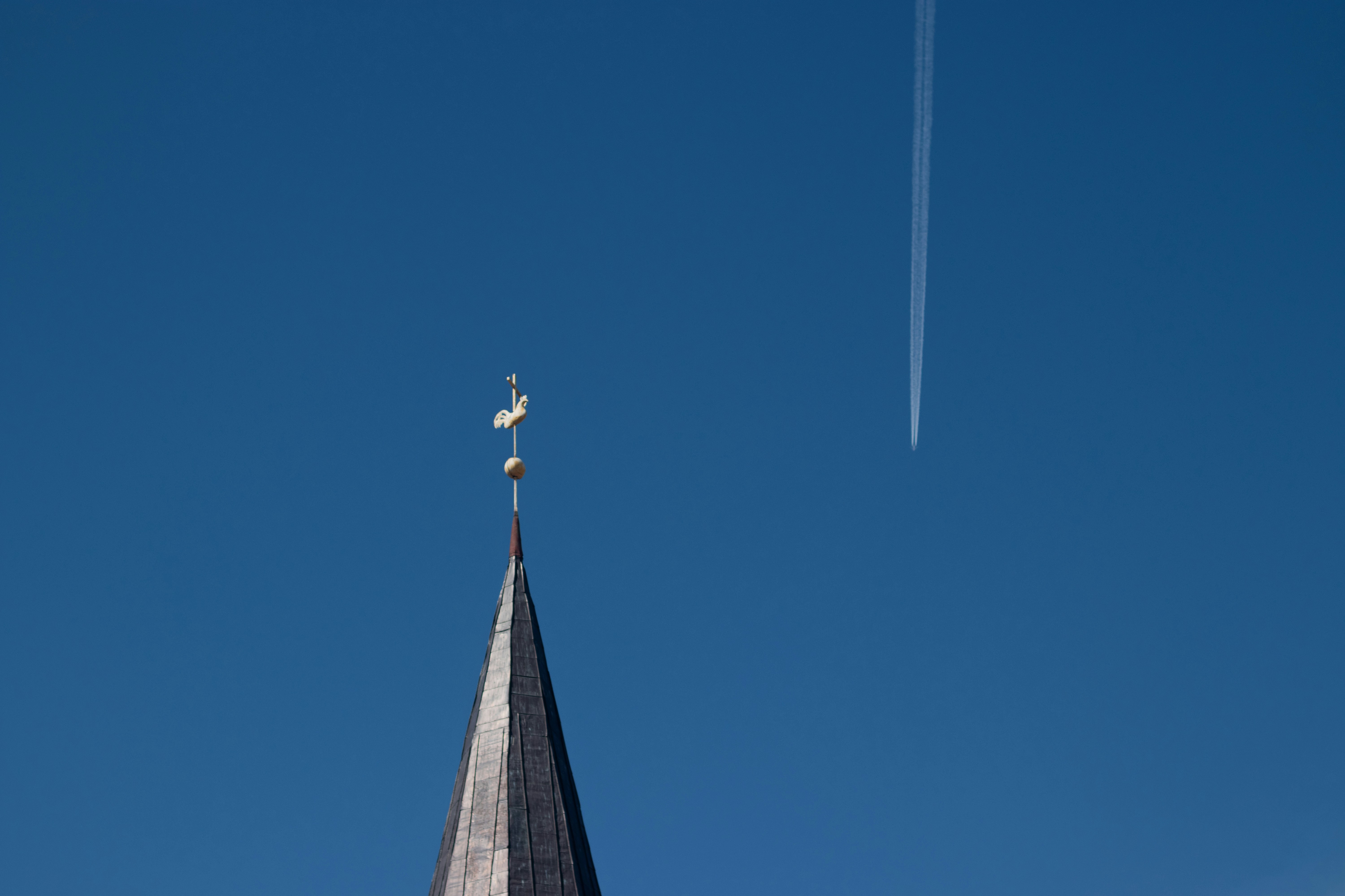Spire Against the Sky: A Sharp Peak Beneath a Jet Trail