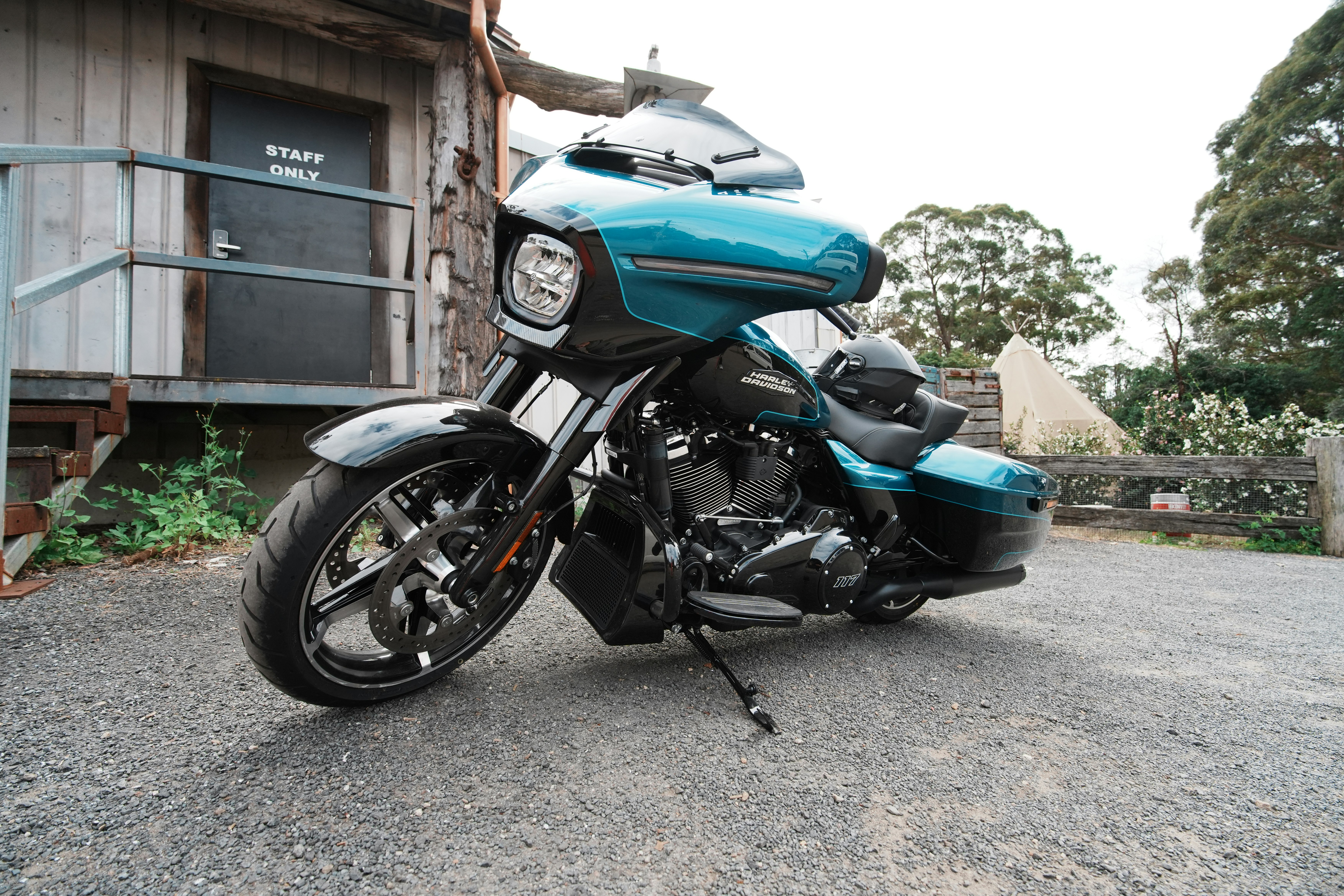 Turquoise Voyager: A Sleek Harley-Style Tourer on a Rustic Pad