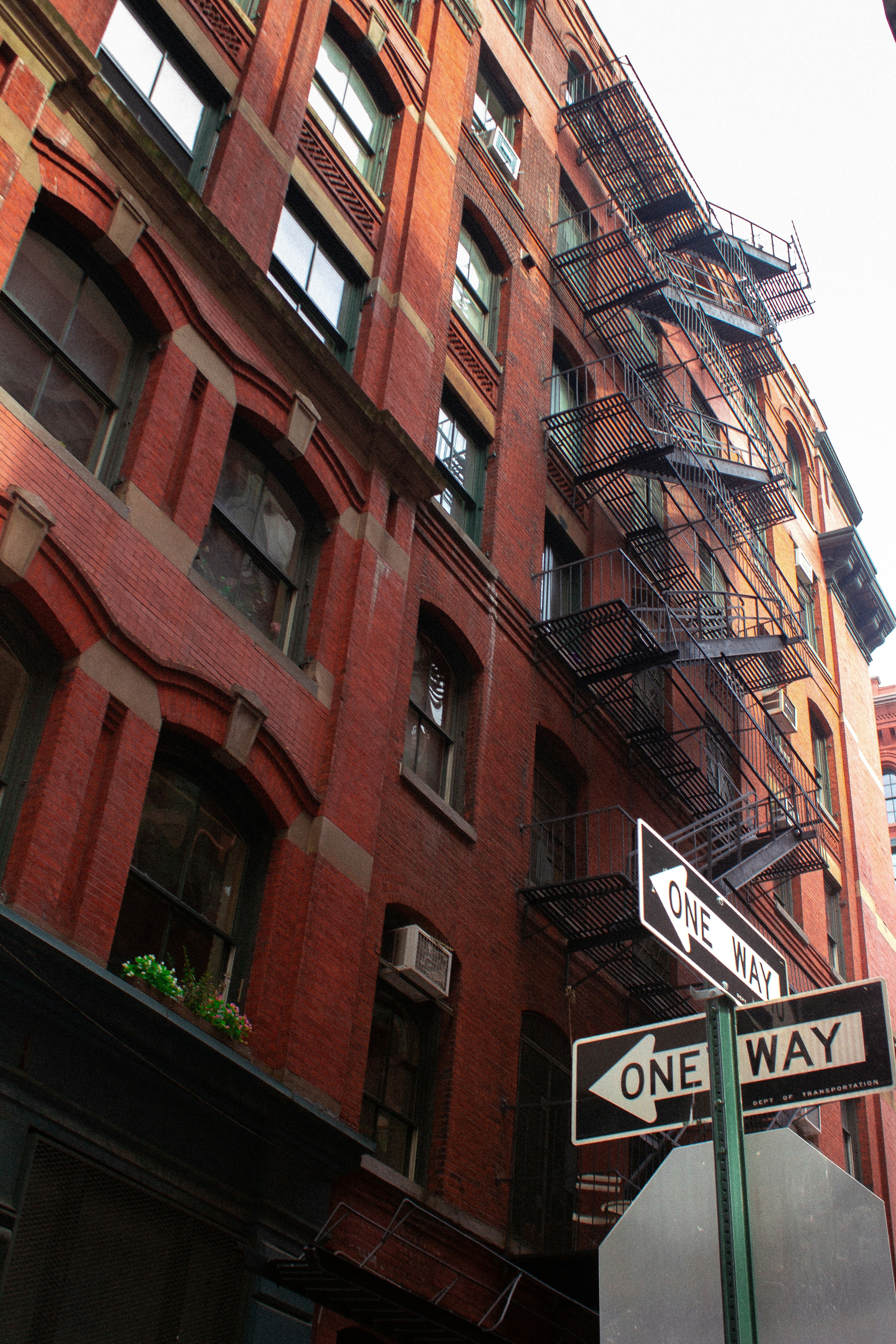 Brick Facade and Fire Escape Lines along a Narrow Urban Street