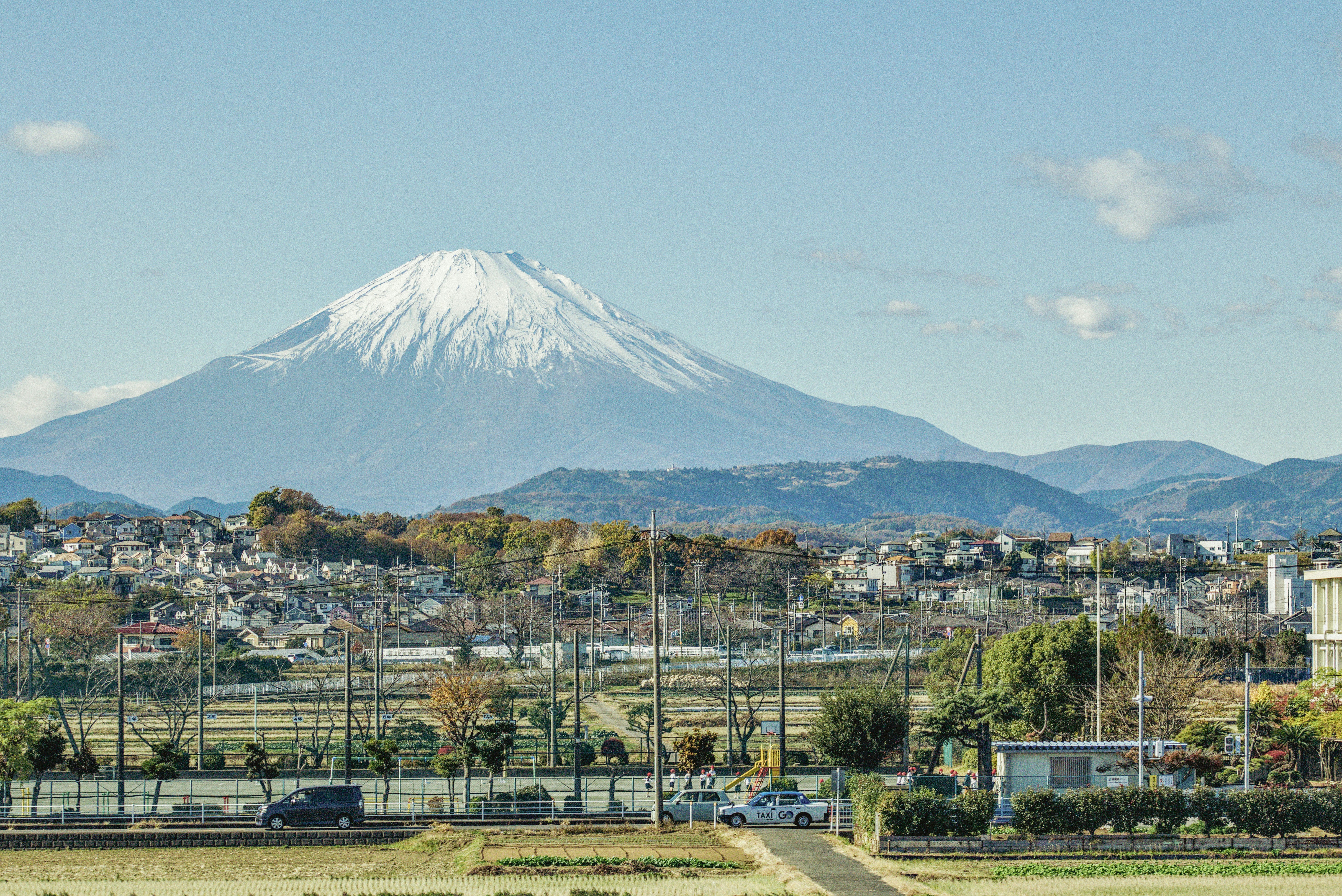 Snowcap Over Suburban Valleys: Mountain Rise Behind a Quiet Town