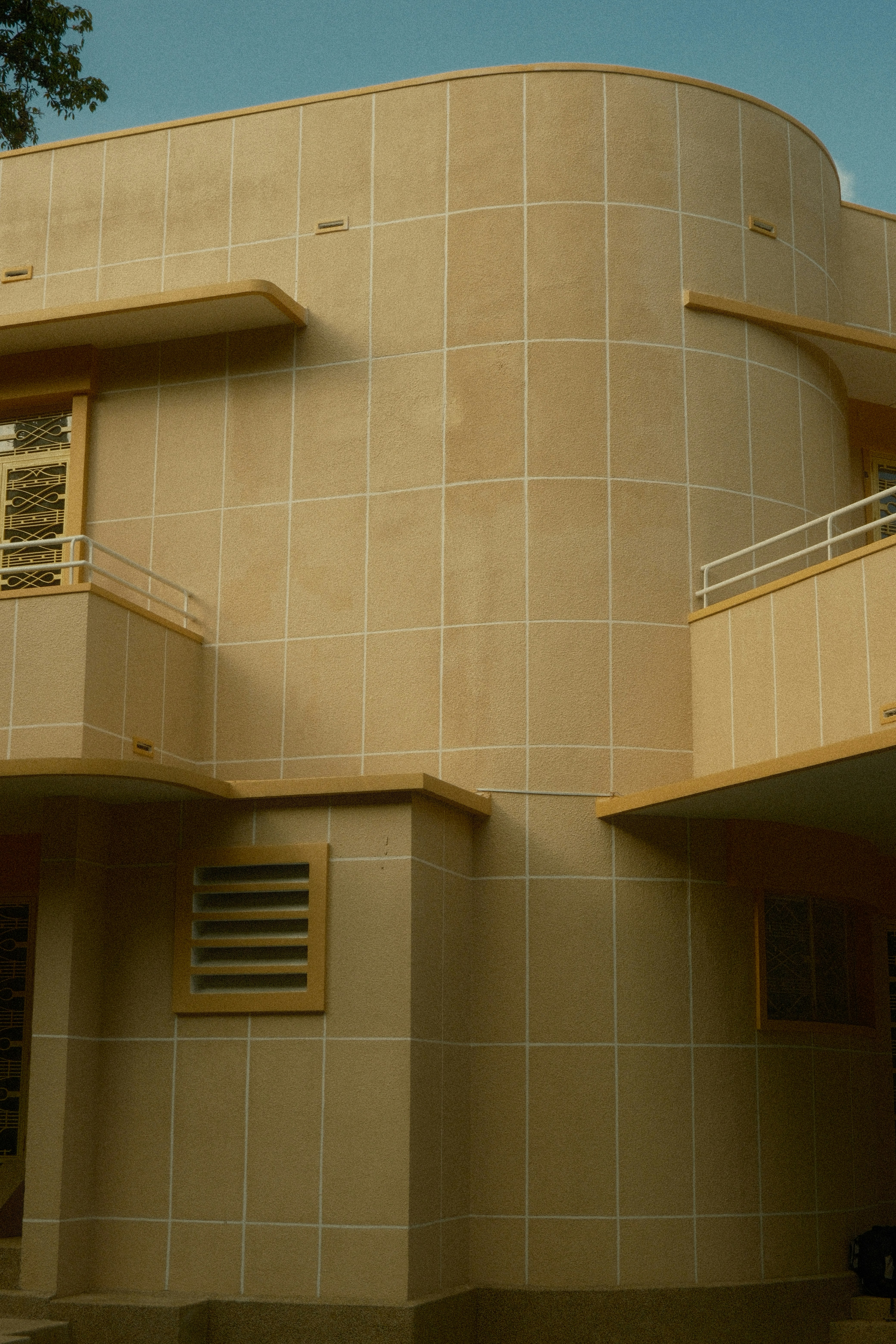 Sunlit Curves and Grid Lines: A Beige Facade Under Clear Sky