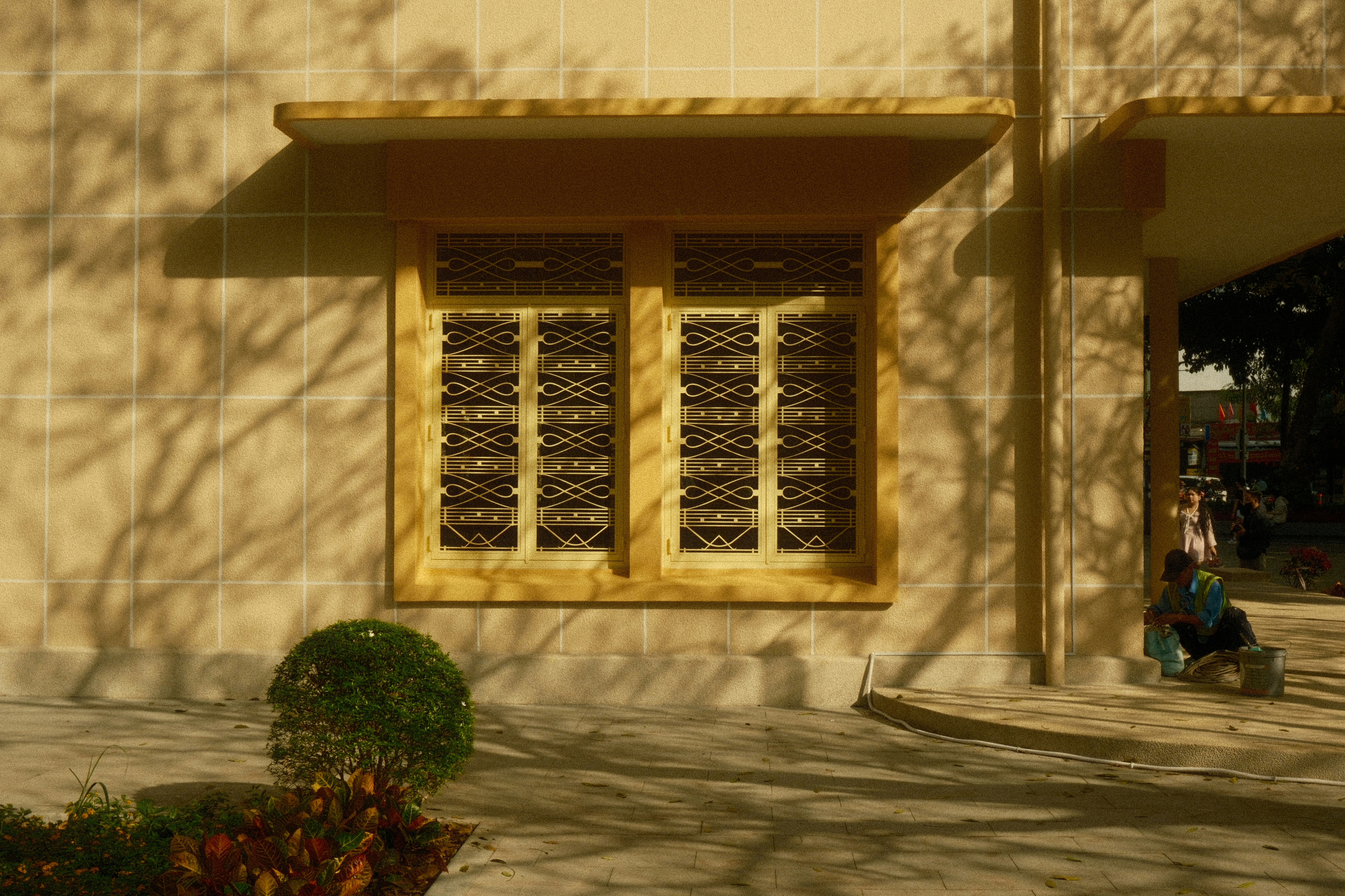 Sunlit windowed facade with carved grills and quiet courtyard shadow