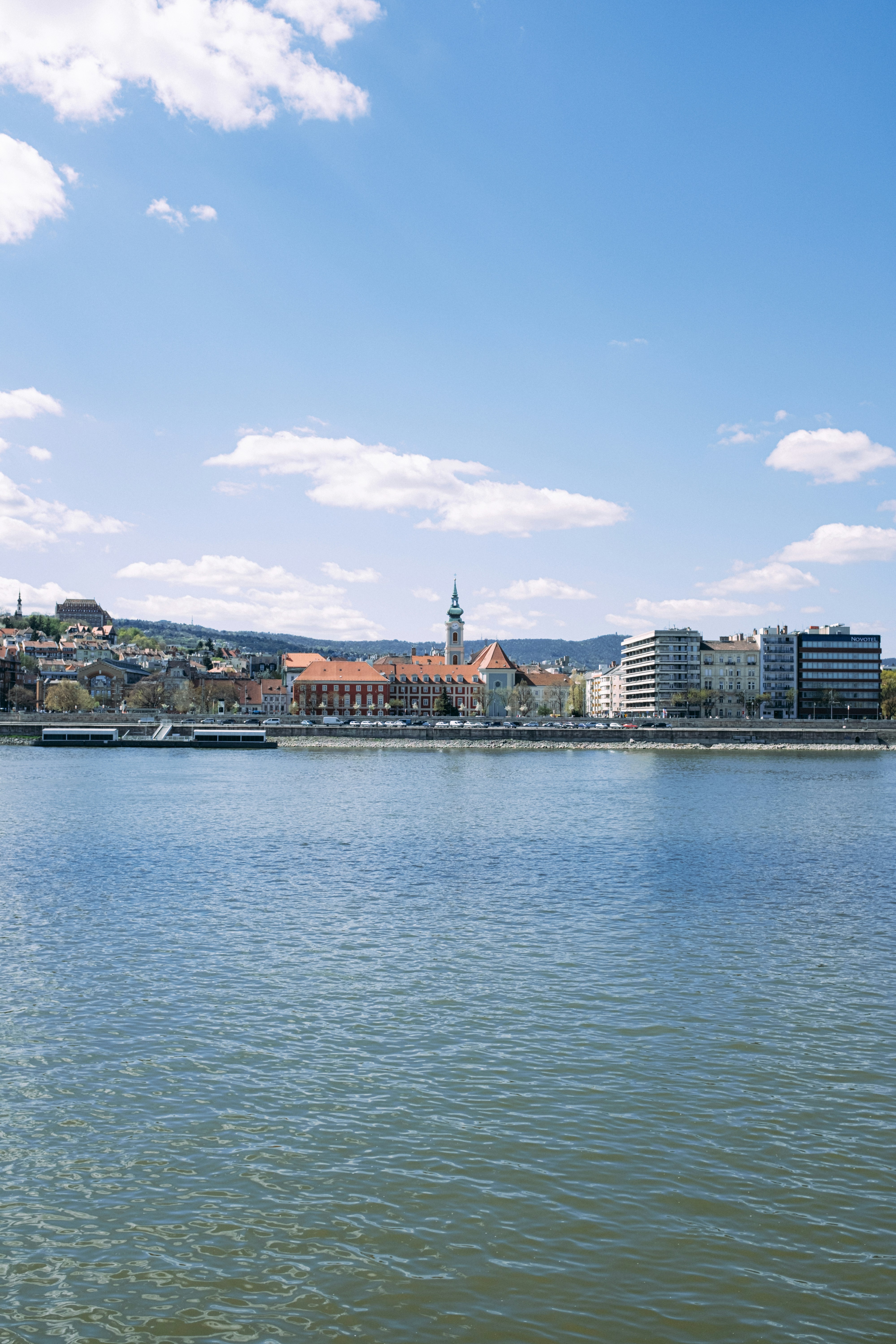 Cityscape Across the River: A Quiet Skyline Under a Blue Sky