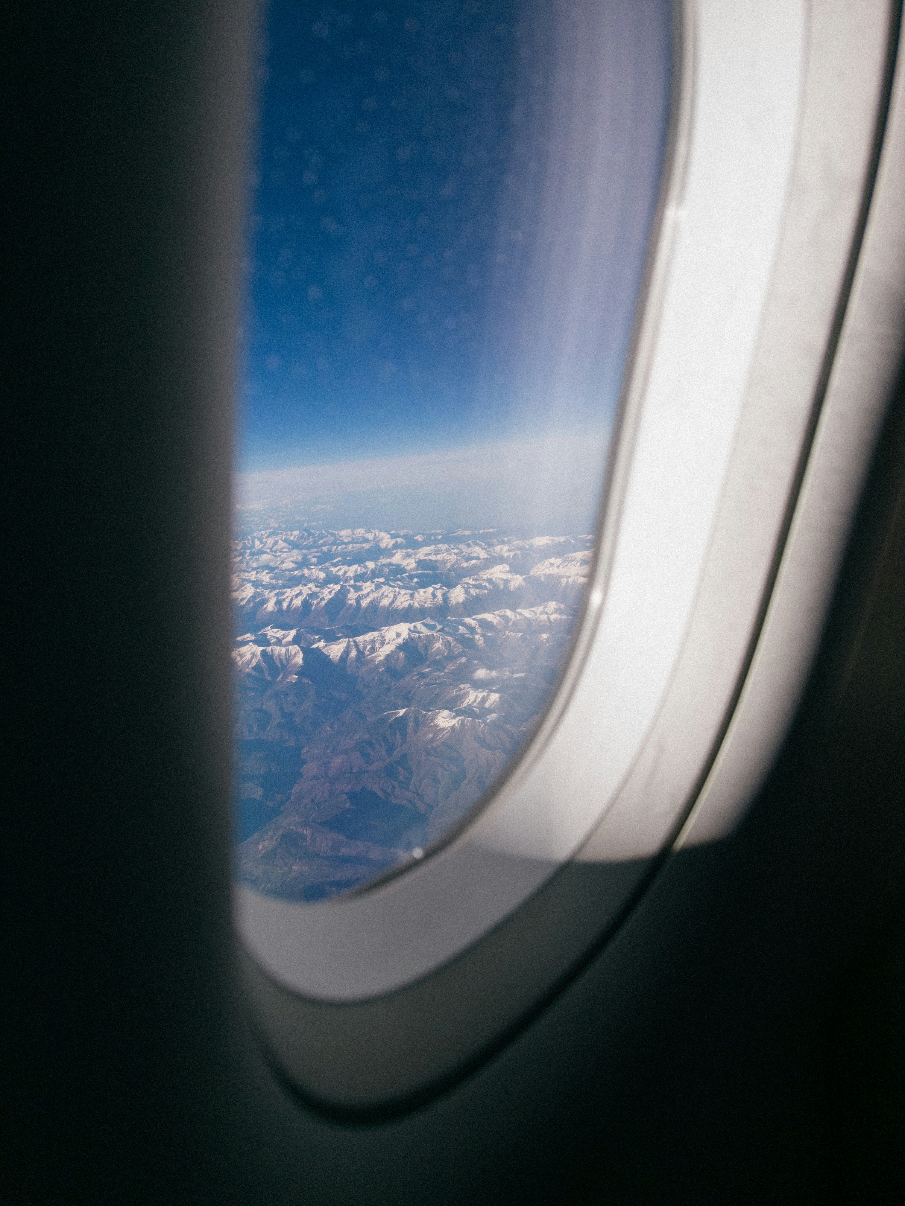 Window to the Range: Snow-Capped Peaks Beyond the Airplane Pane