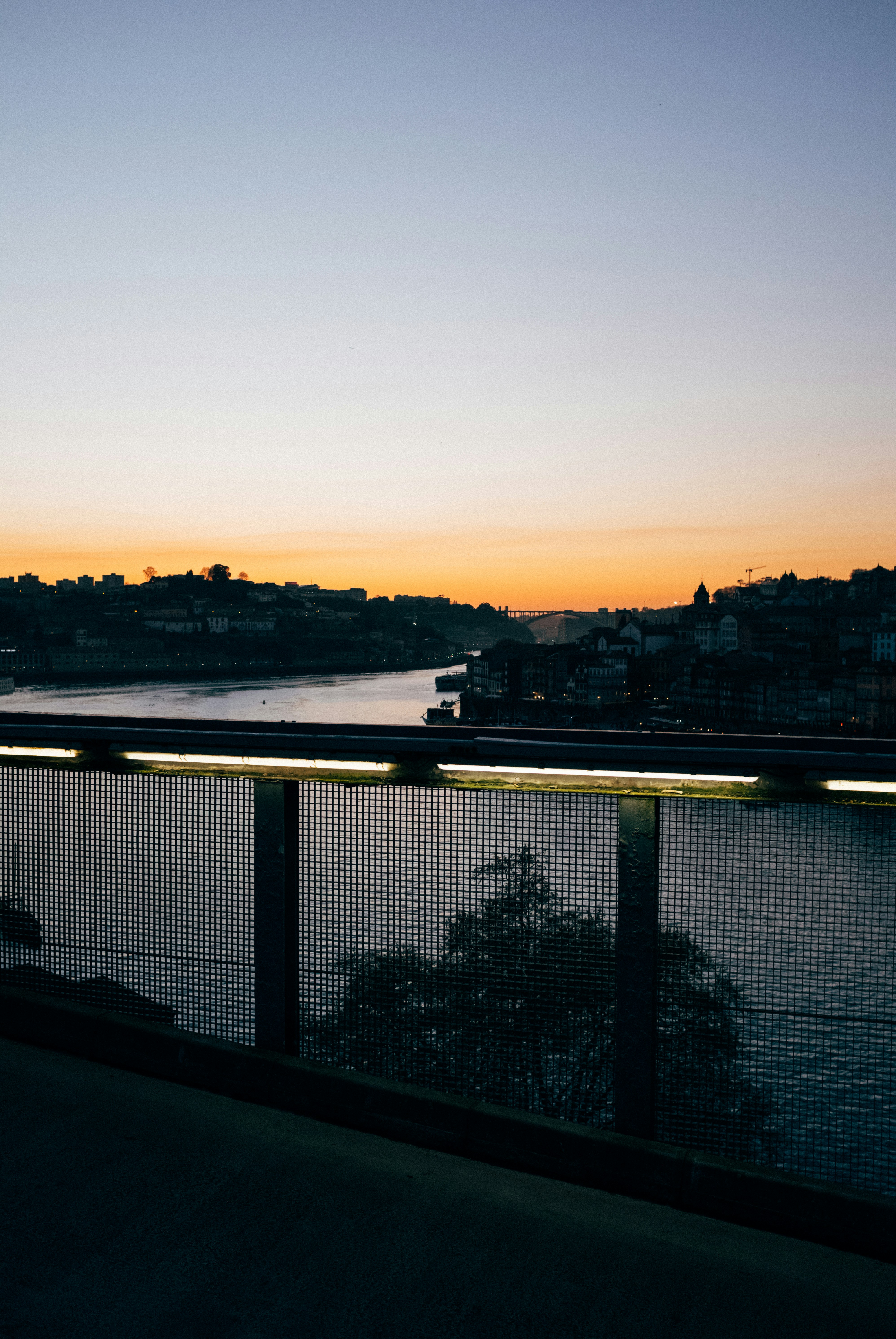 Sunset Over the Railing: City Silhouette and River