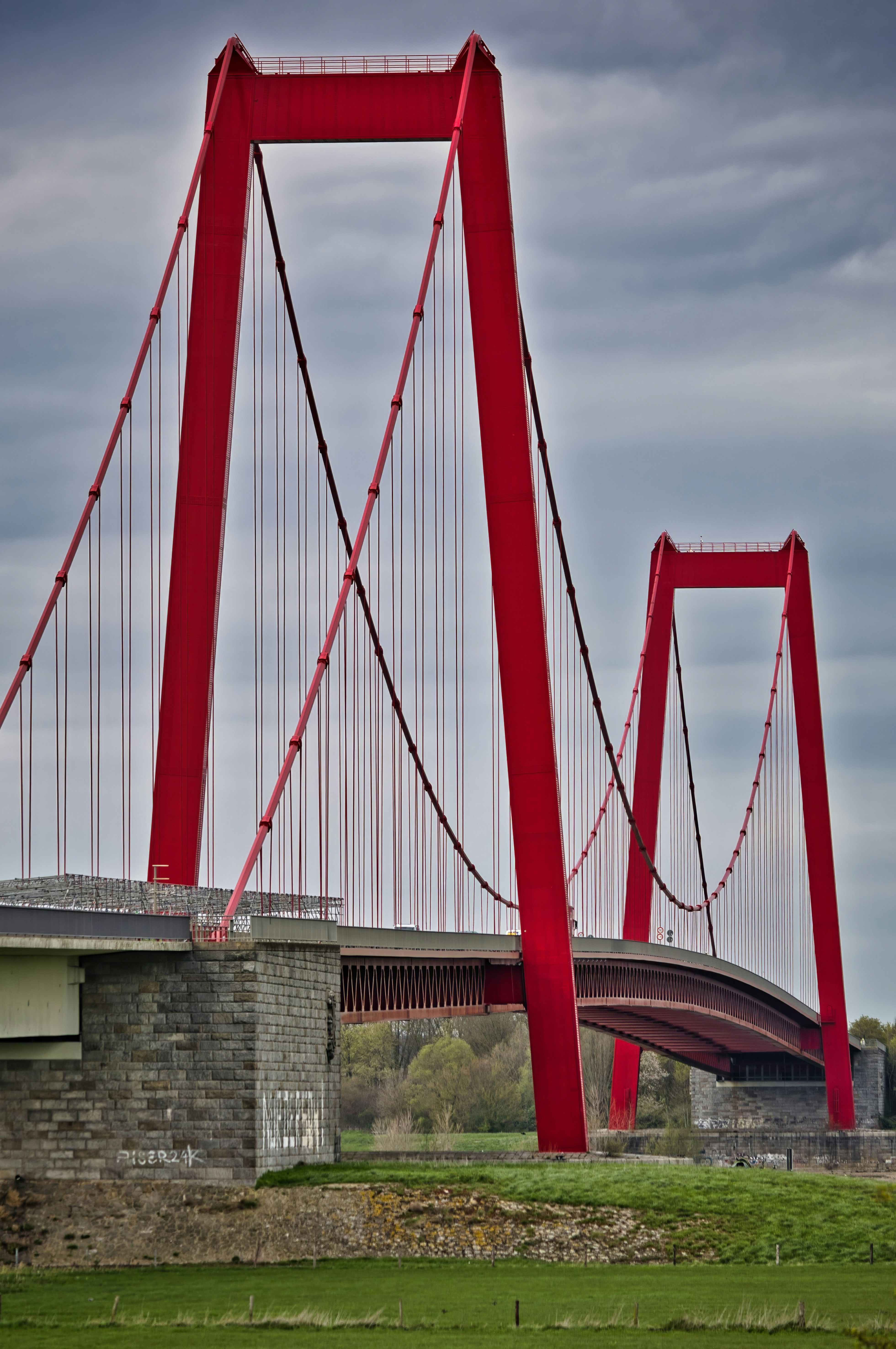 Crimson Arches: a Red Suspension Bridge Stretches Across a Quiet Landscape