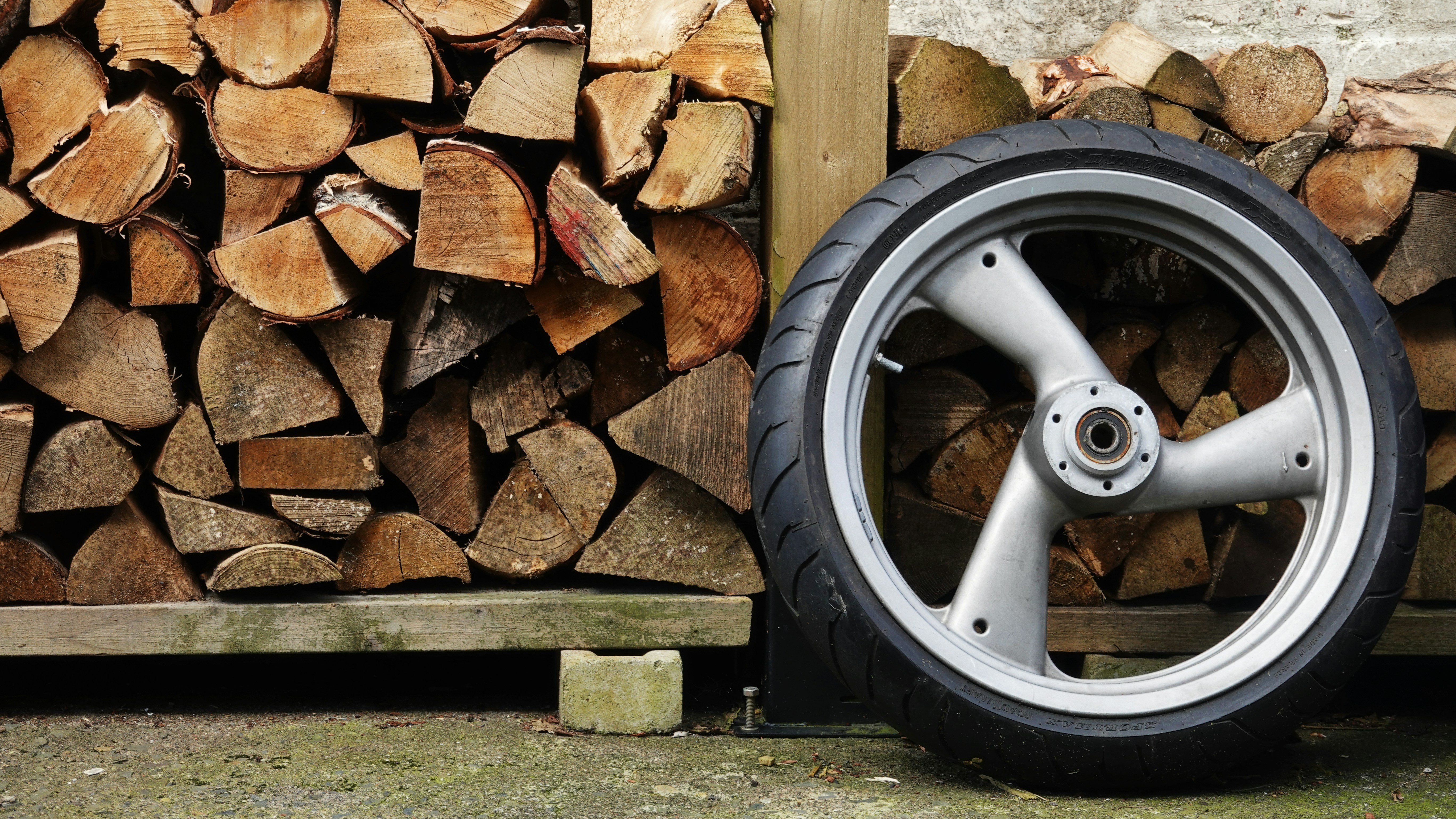 Wheel of Logs: A Quiet Stack of Firewood by a Single Tire