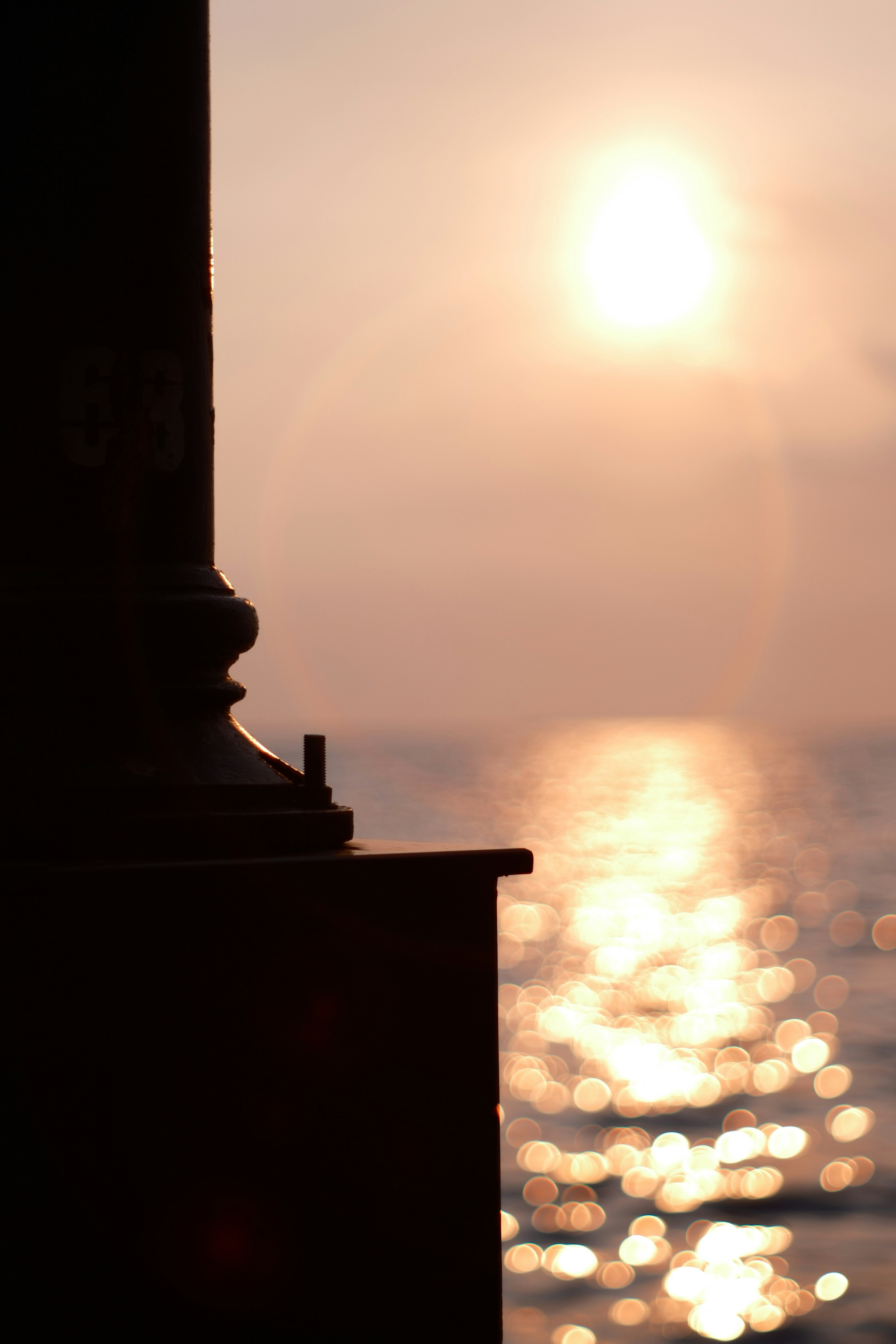 Sunlit silhouette by the pier: a warm horizon and reflective water