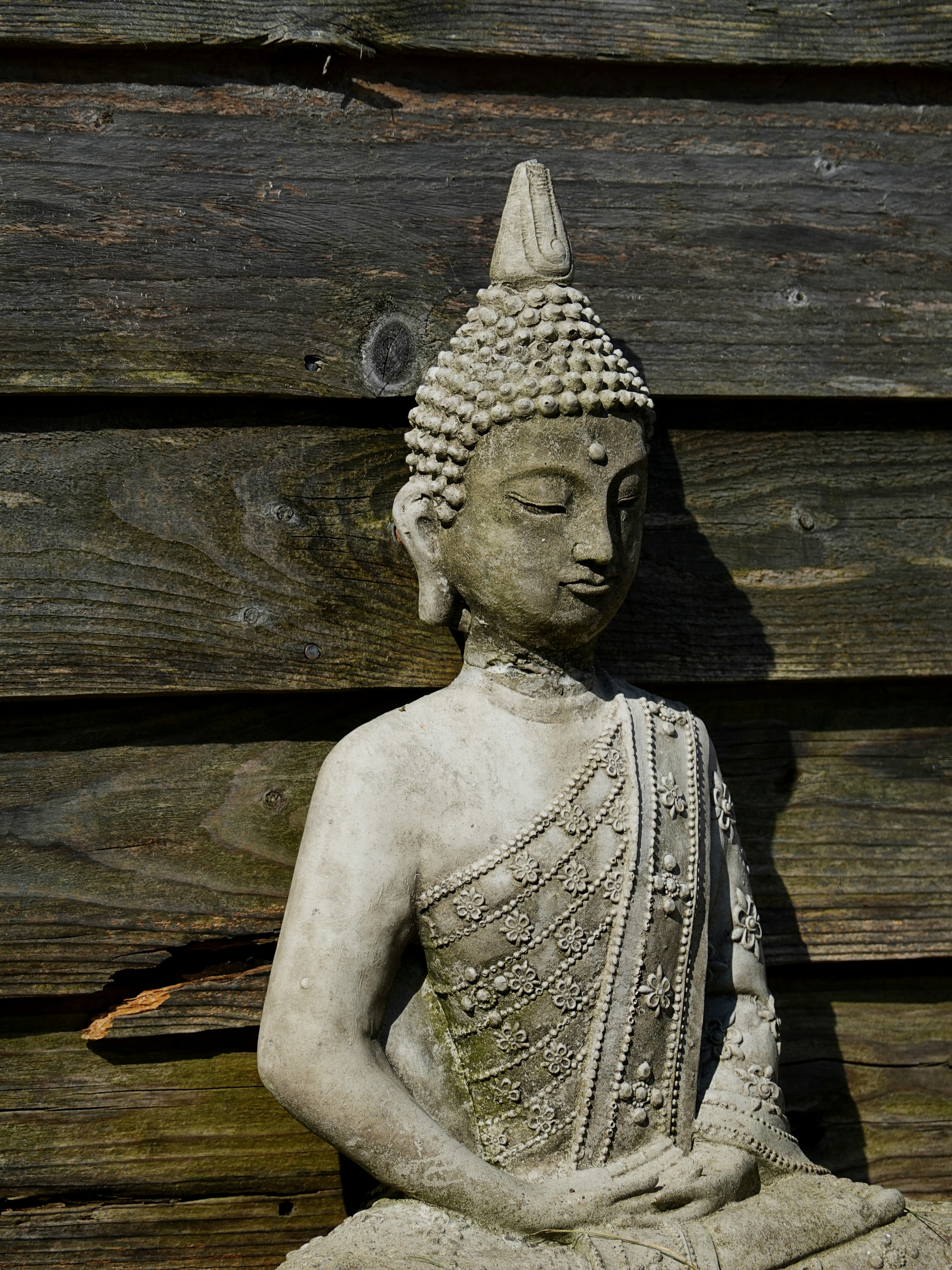 Meditative Stone: a Buddha statue against weathered planks