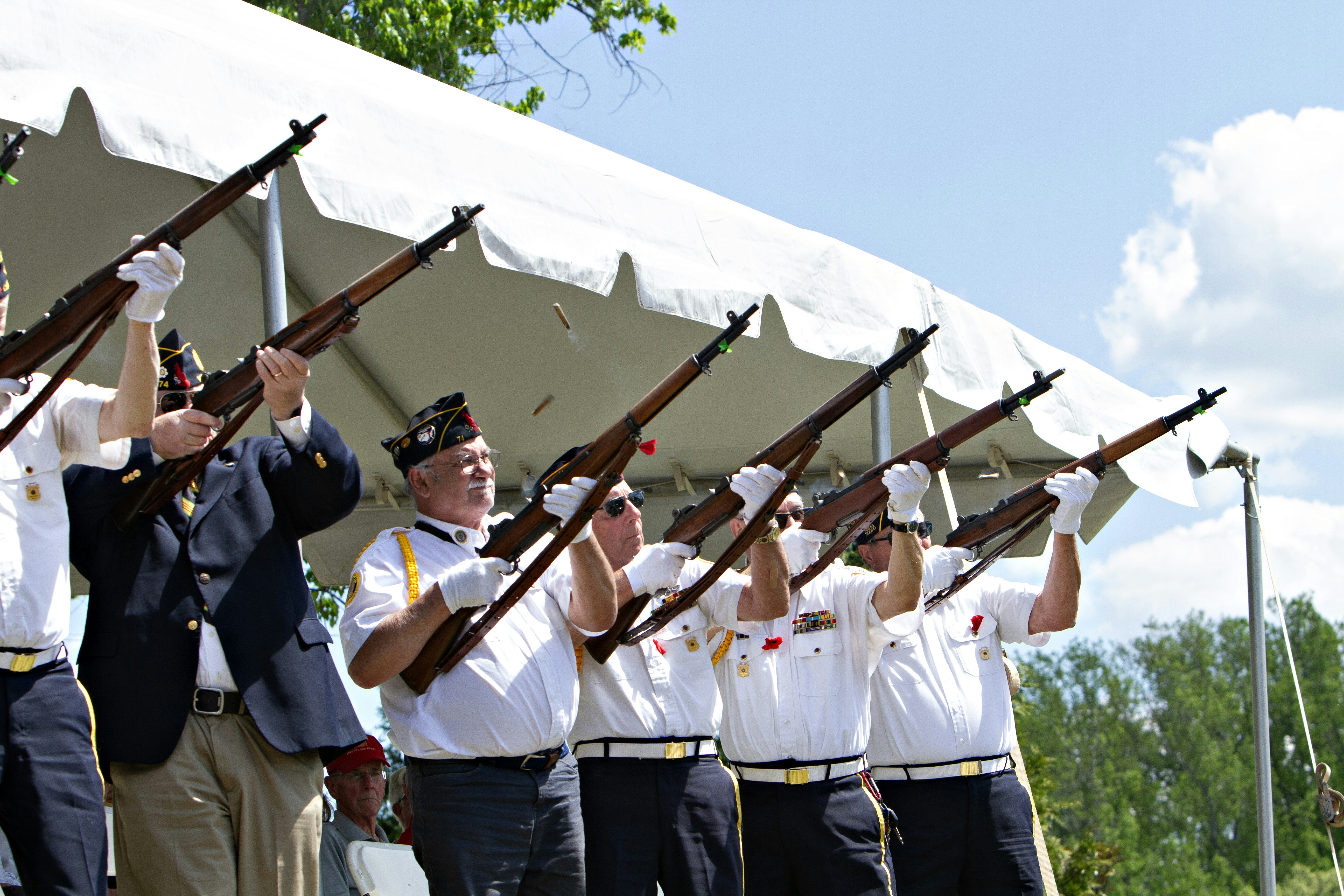 Coordinated Rifle Salute Under a White Canopy