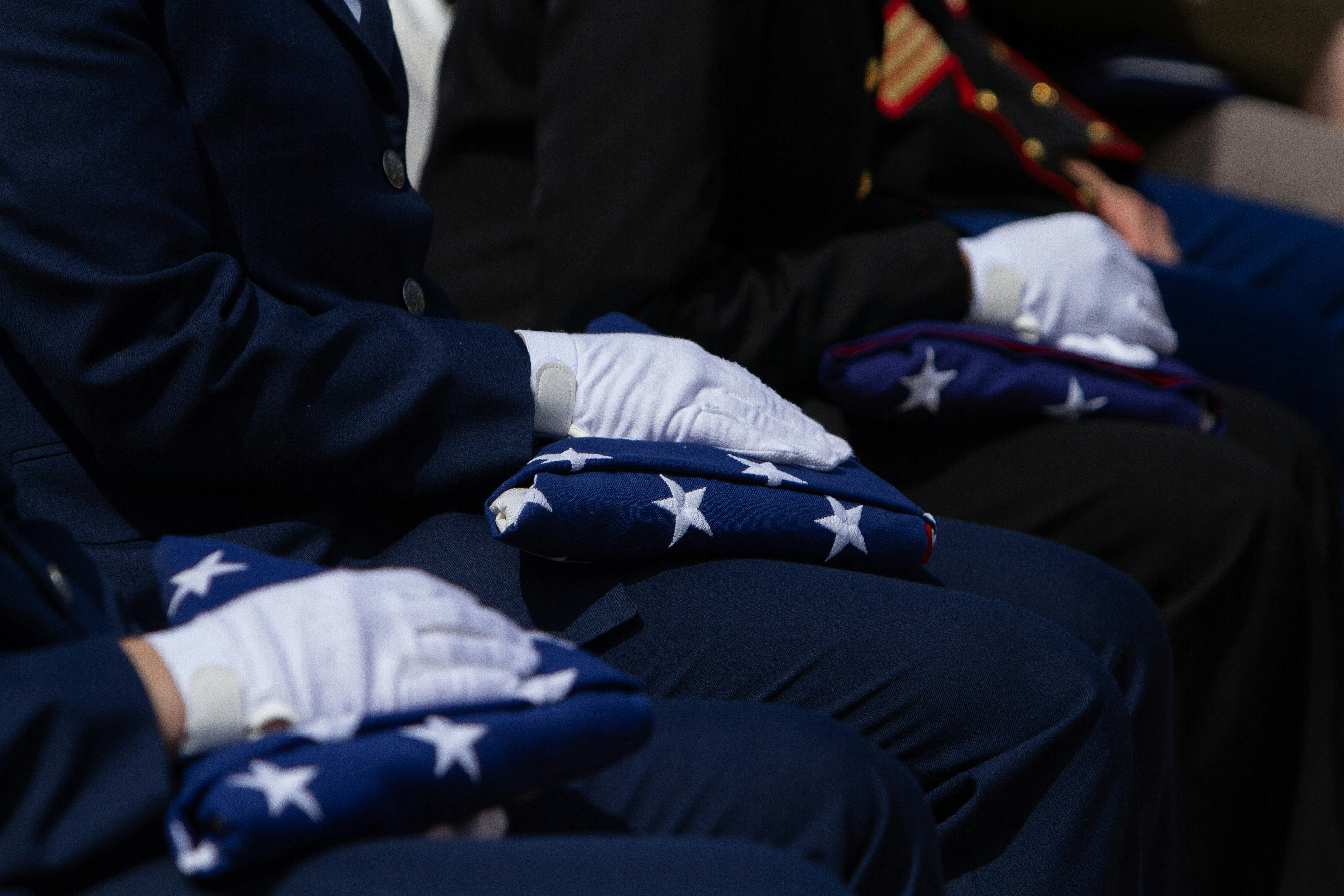 United Ceremony: Hands in White Gloves Resting on Folded Flags