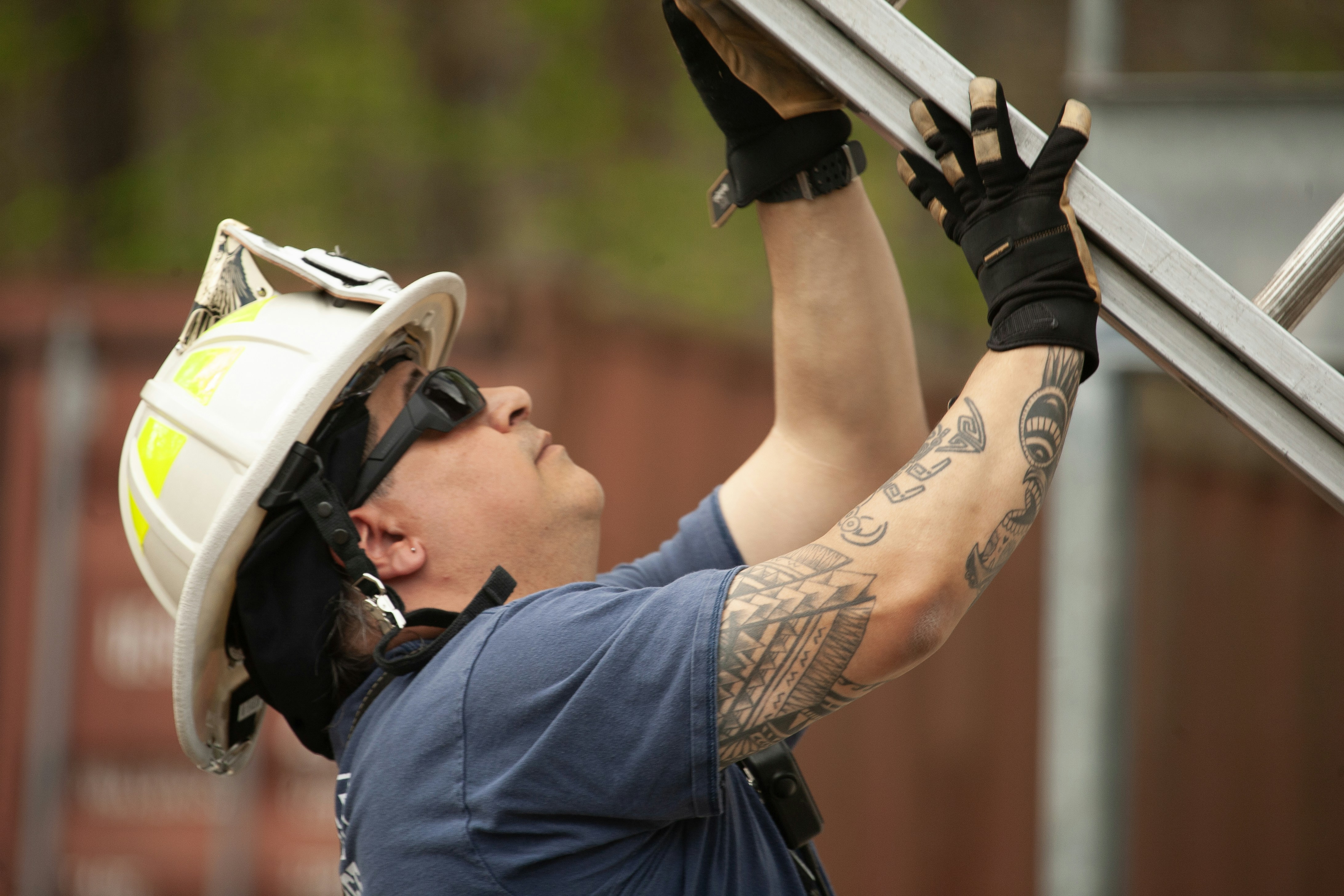 Climbing a scaffold: tattooed worker guiding a steel beam