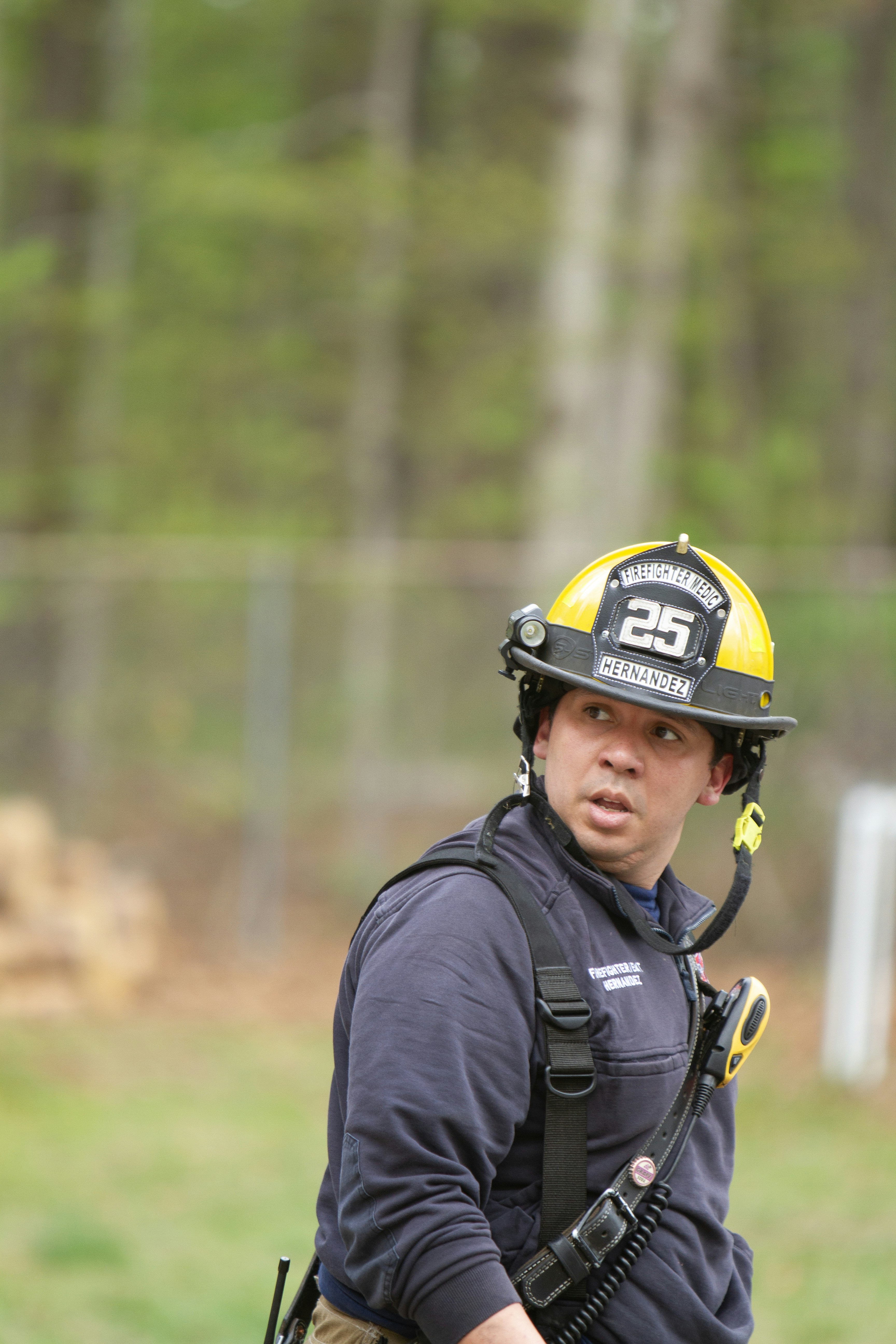 Helmeted Responder Looks Back Over Shoulder in Forest Training Ground