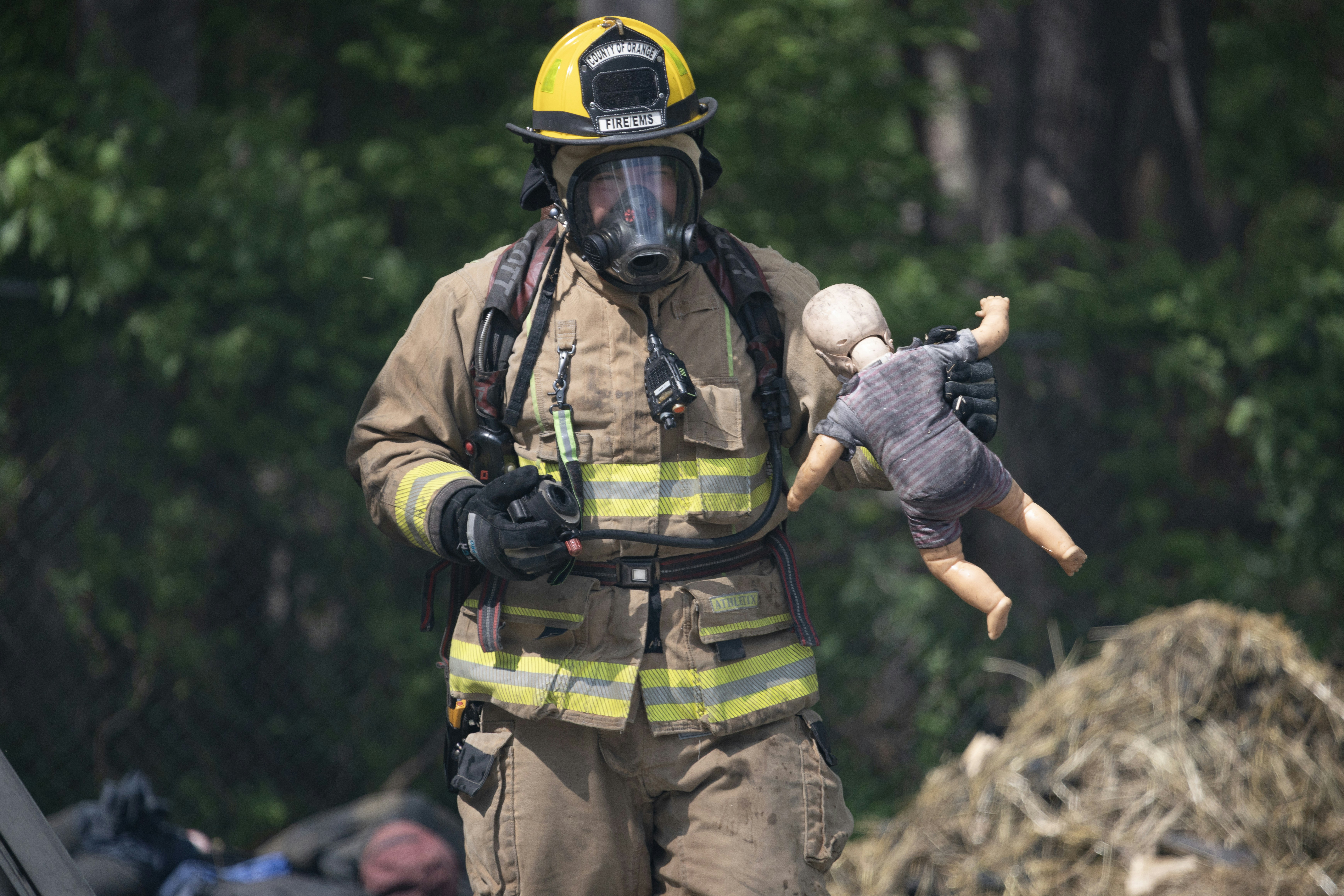 Firefighter in Full Gear Calibrates Rescue Drill with Staged Doll