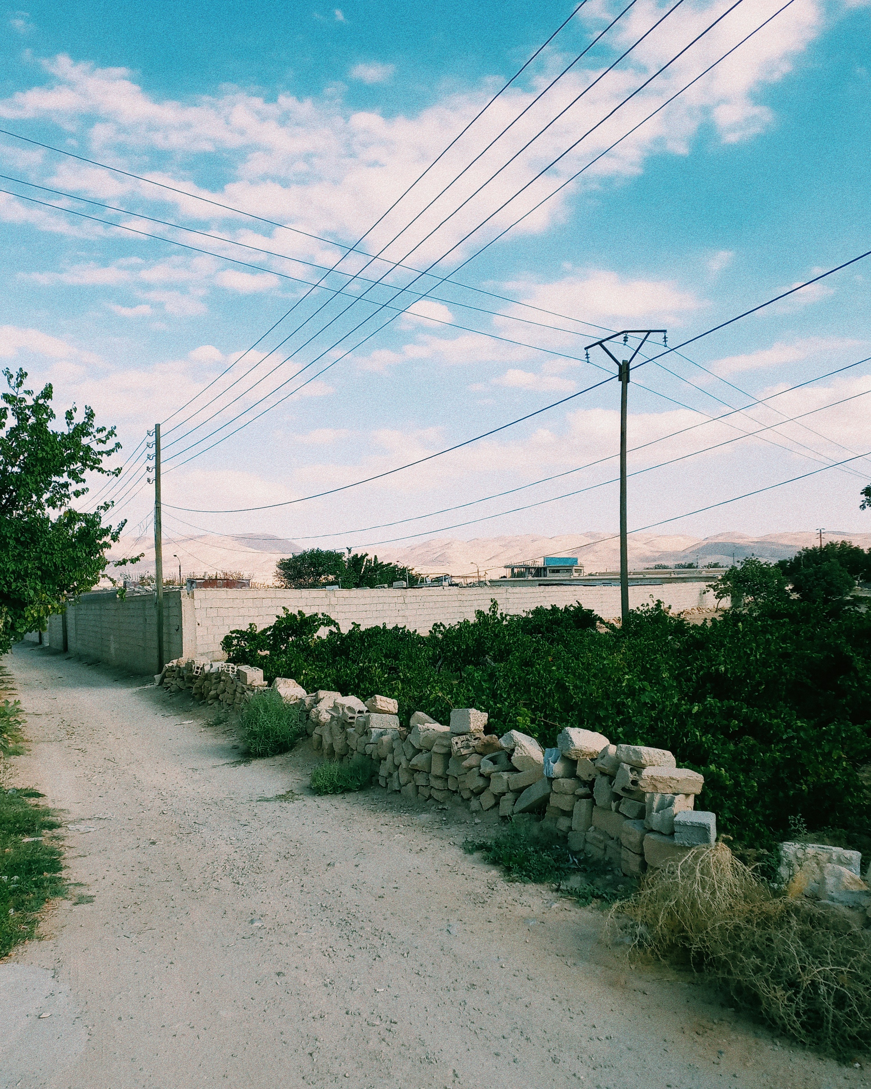 Dusty Path to Distant Hills Under Wire-Topped Sky