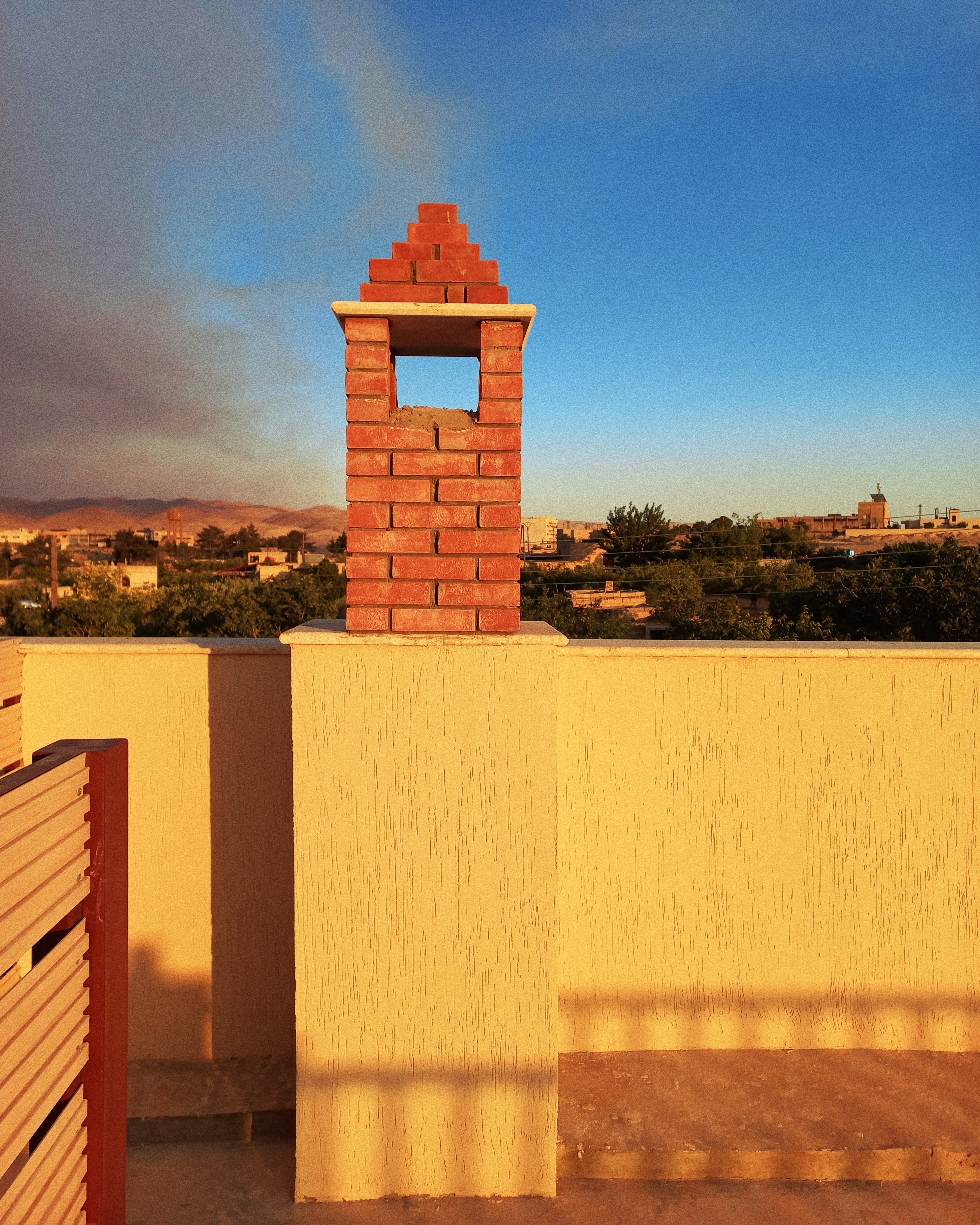 Brick Chimney Rising Above Sunlit Terrace