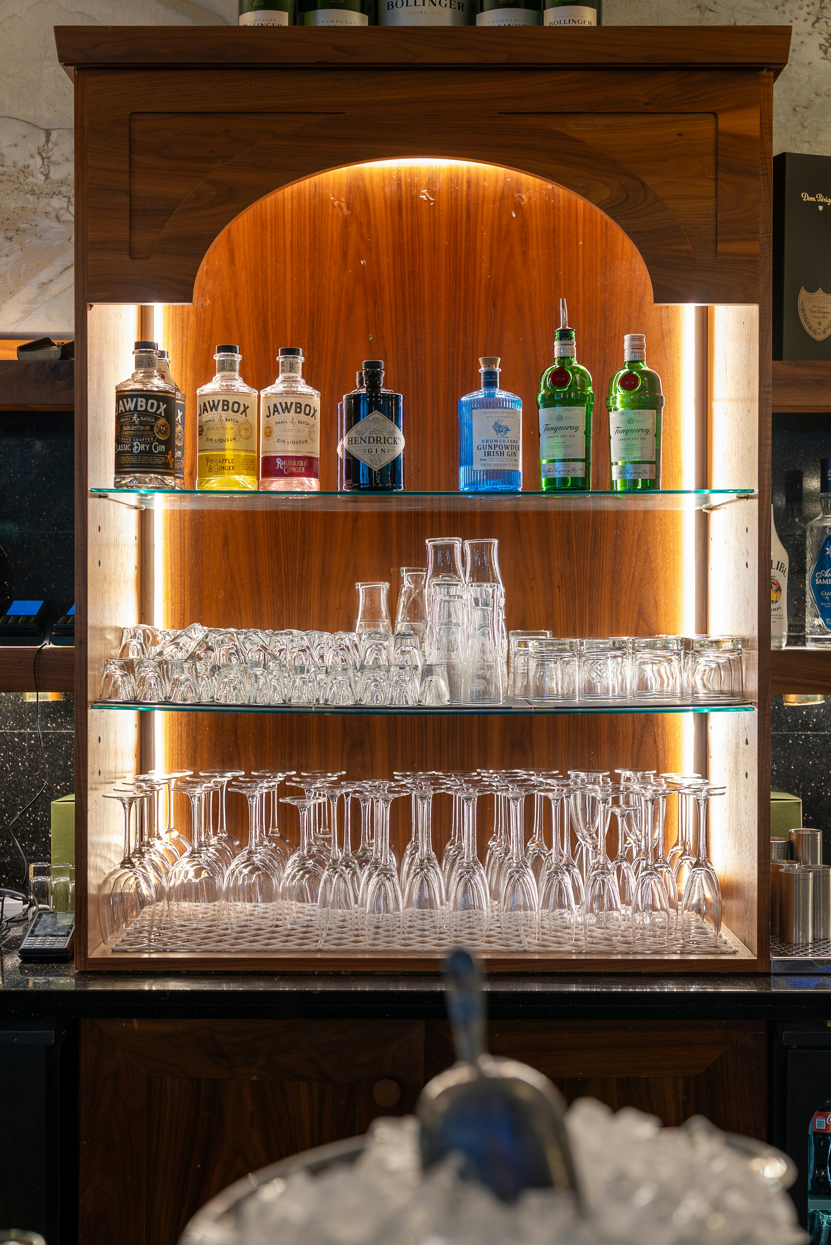 Glass Shadowed Barfront: Bottles and Glassware on a Warm Wooden Shelf