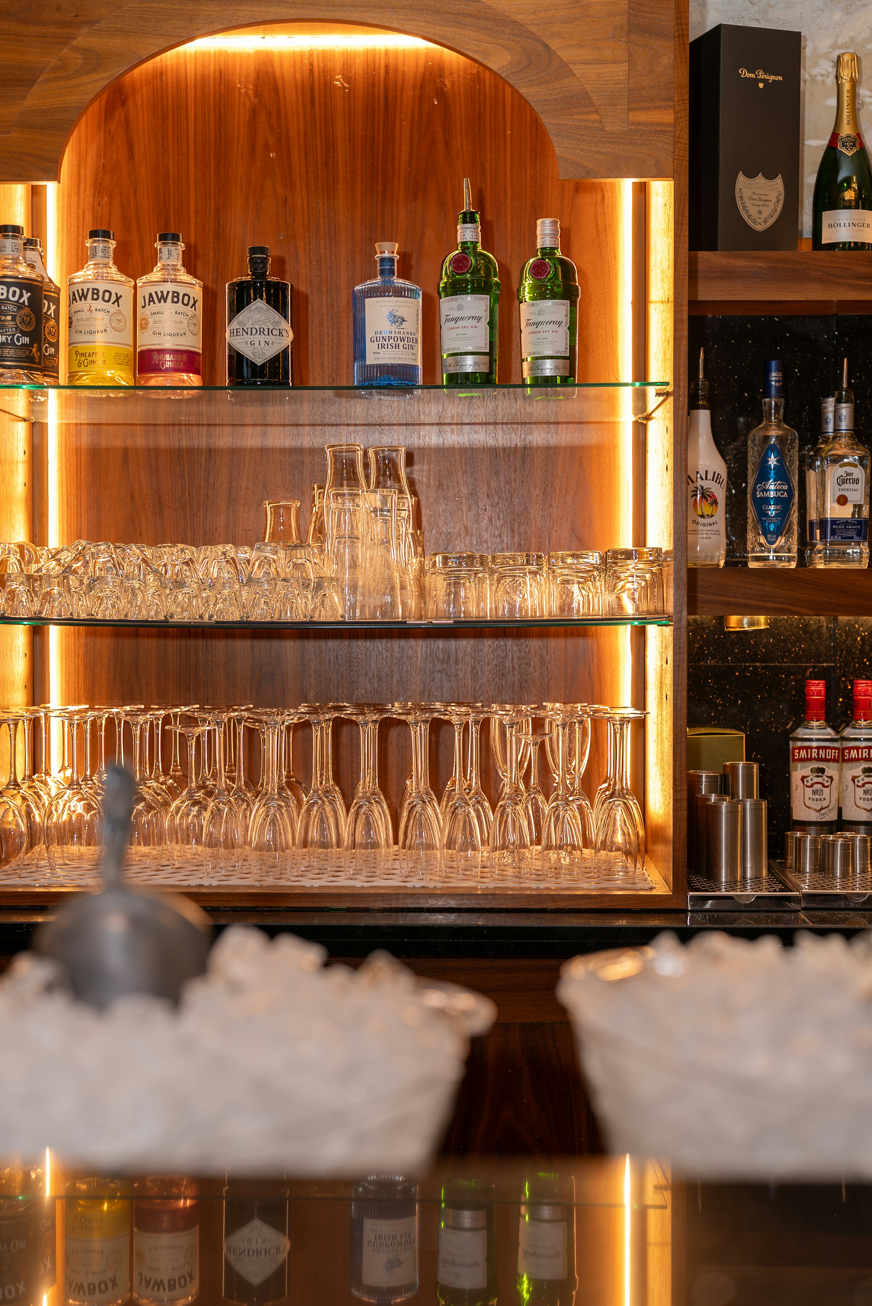Backlit Bar Shelves: Bottles, Glassware, and Ice in warm amber glow