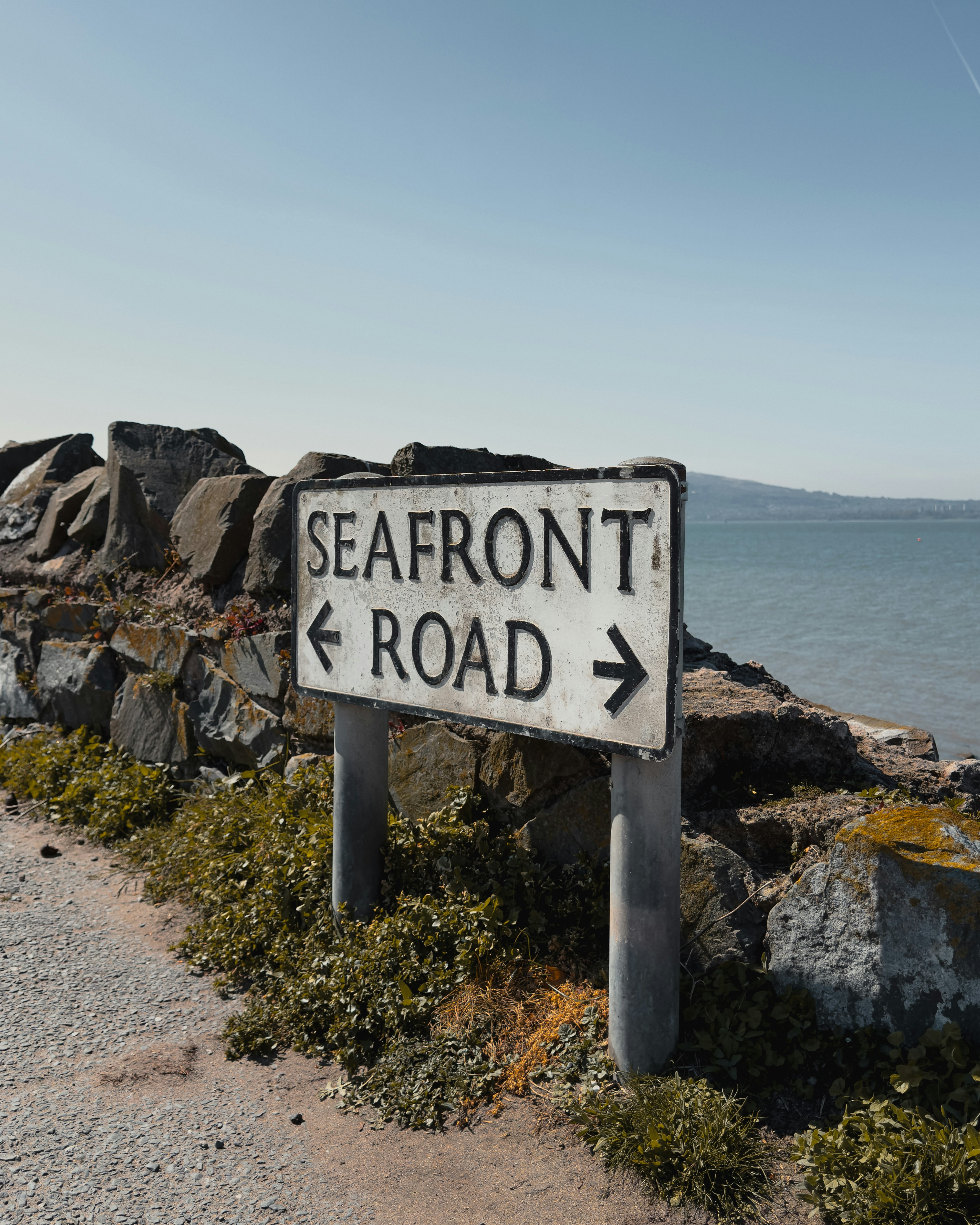 Seafront Road Sign Anchored by Coastal Rocks
