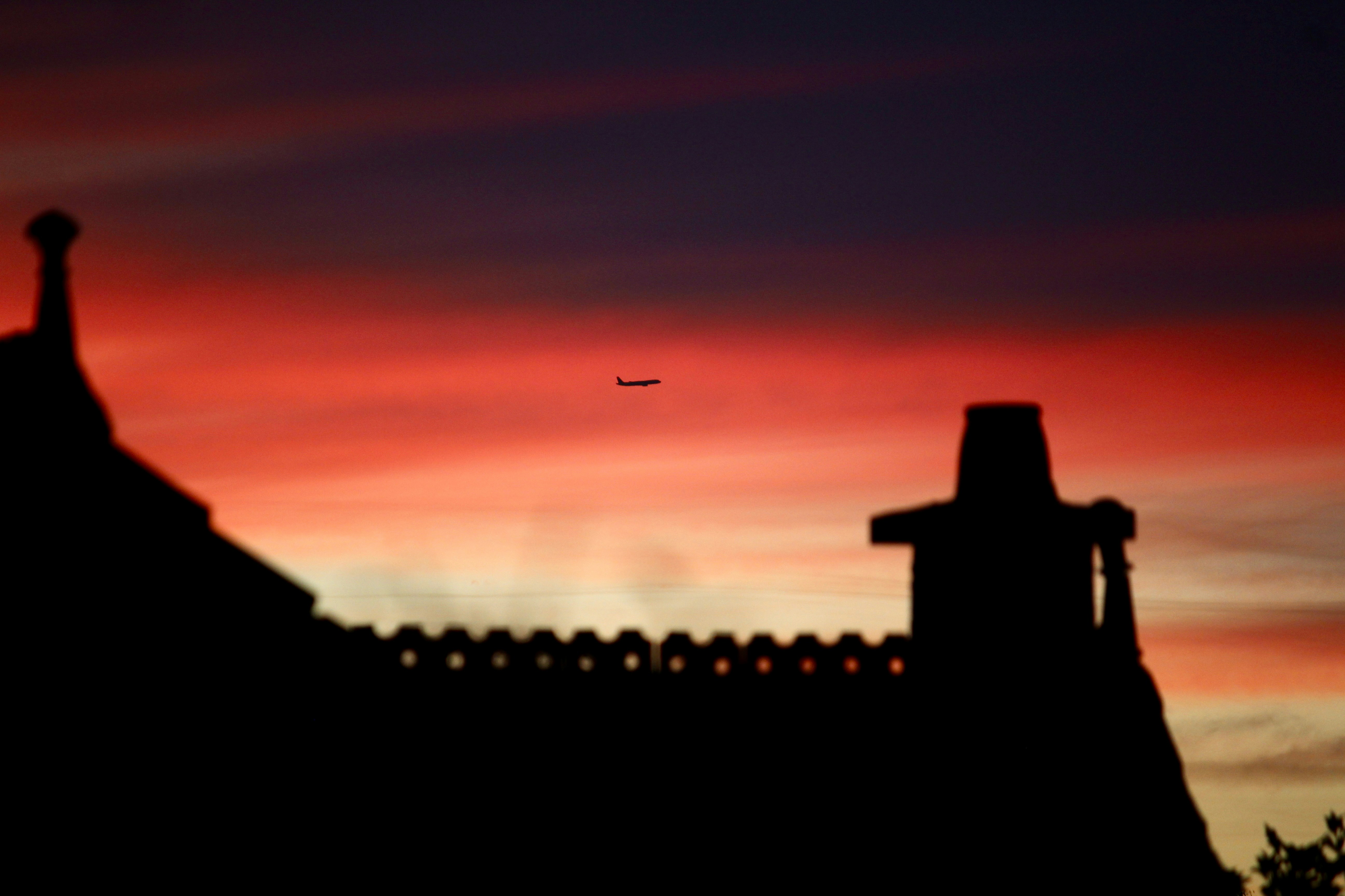 Silhouette at Dusk: A Rooftop Horizon and a Distant Air Whisp