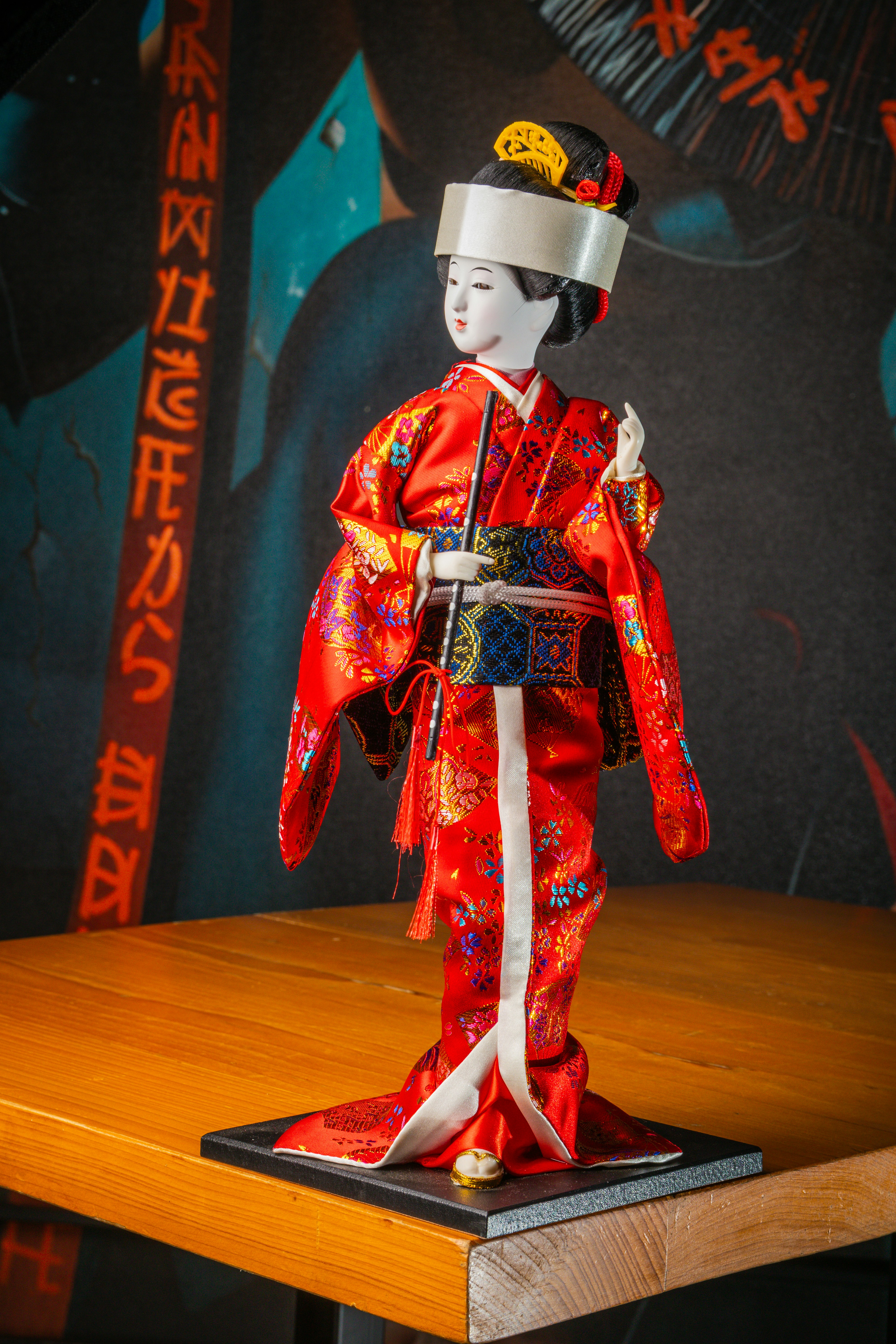 Red Silk Elegy: A Geisha Figurine on a Wooden Stage
