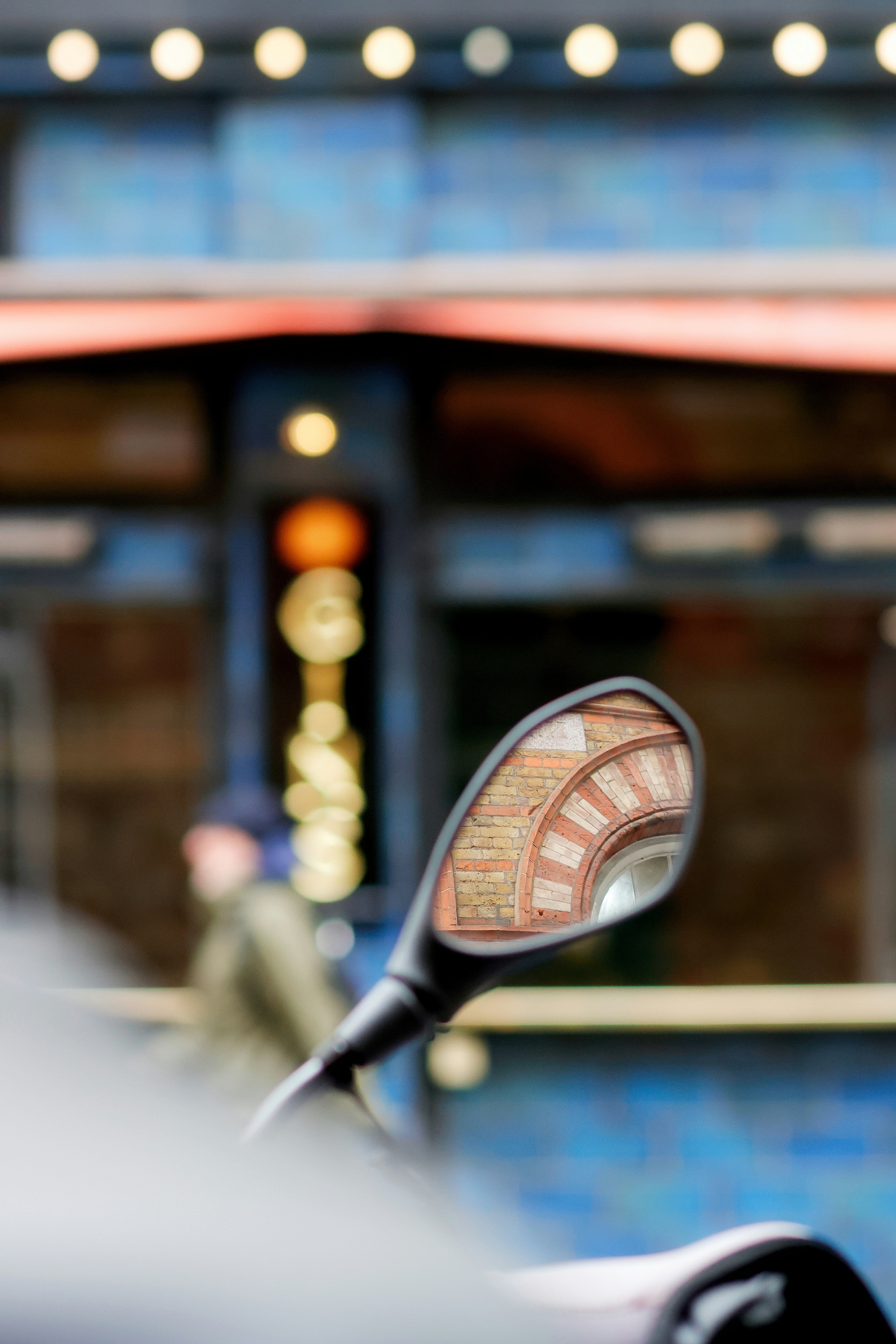 Circle in the Glass: A Motorcycle Mirror Reflects a Brick Arch