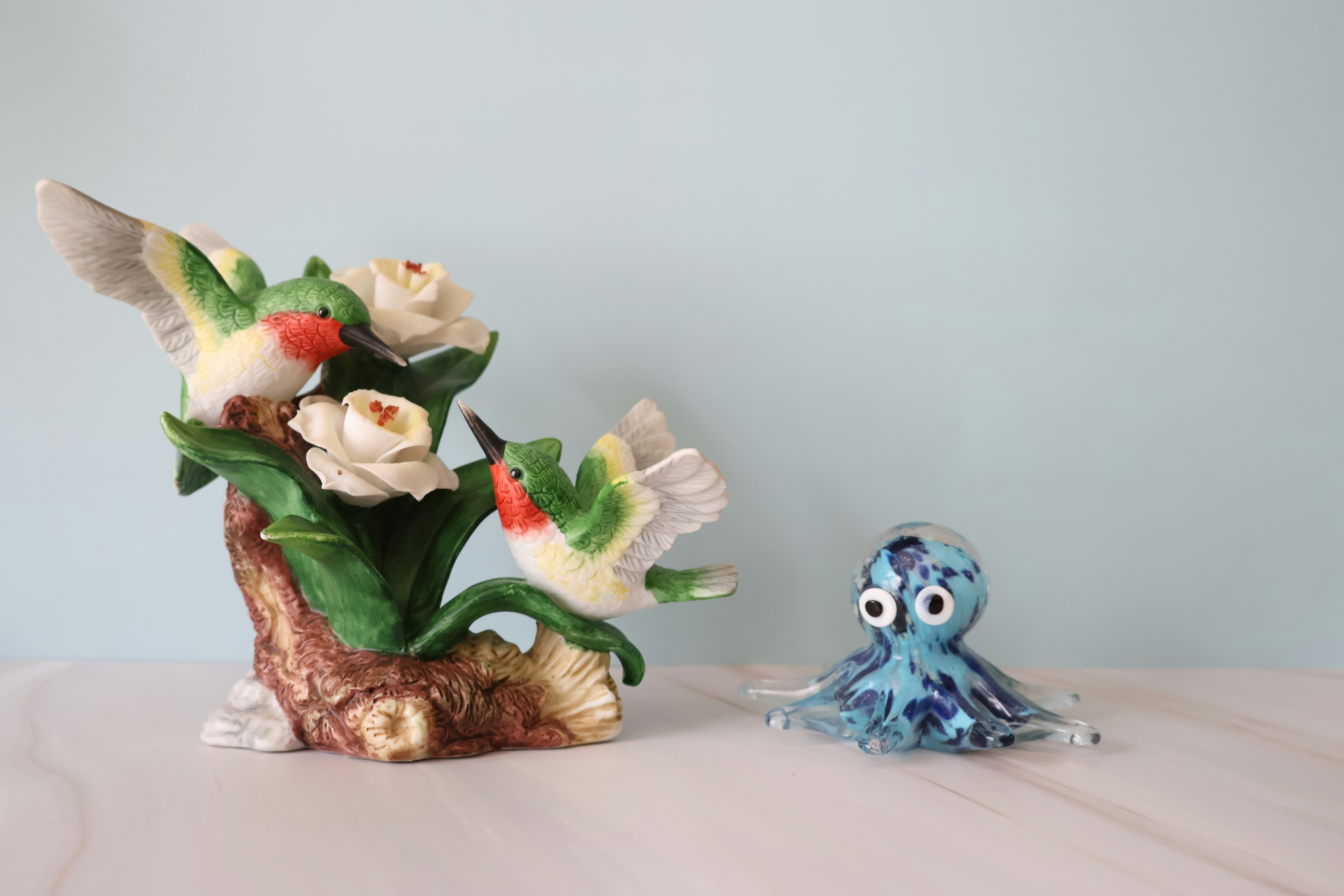 Whimsical duet: hummingbirds and an octopus across a pastel shelf