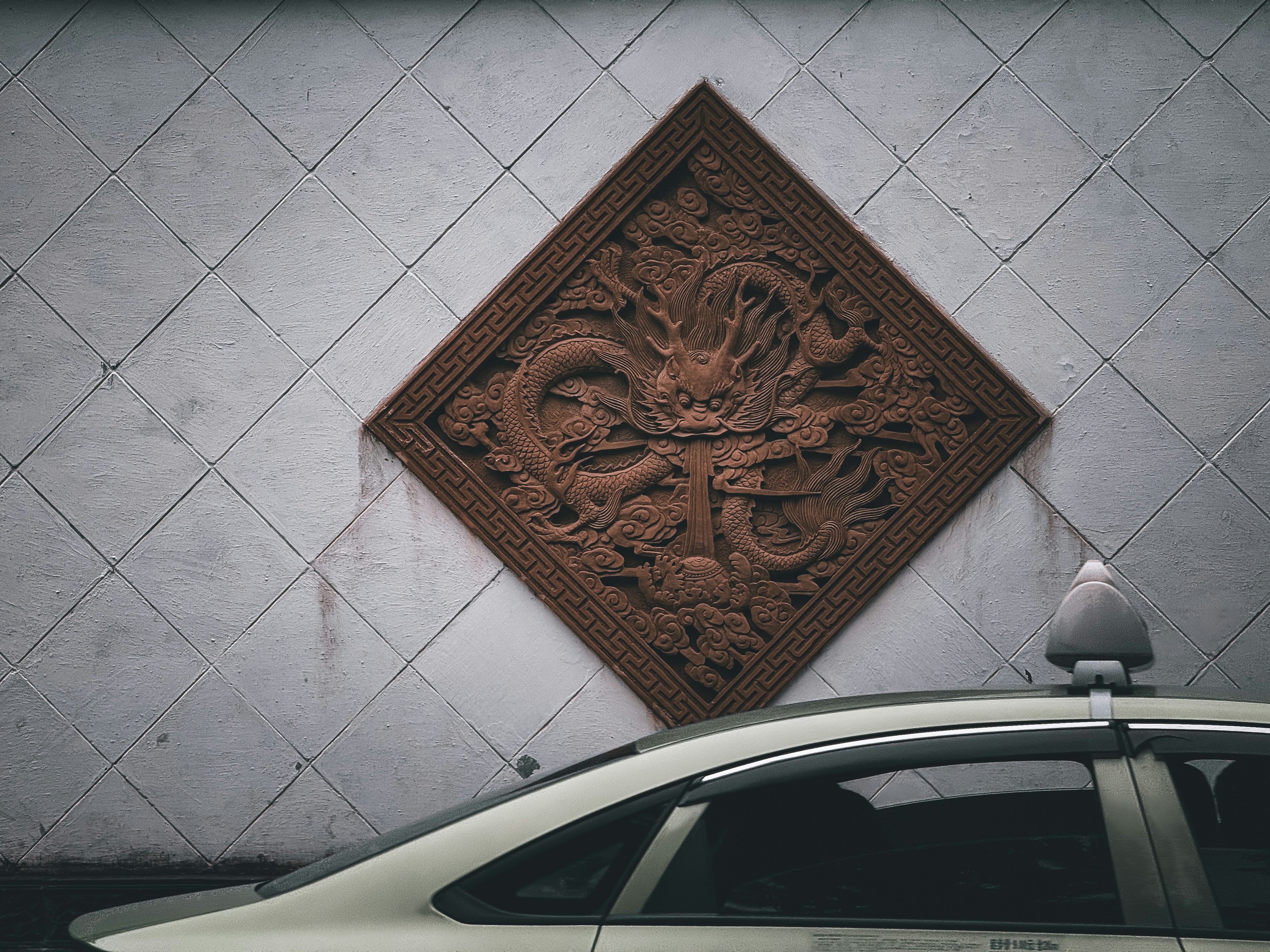 Car, Tile, and Ornate Emblem: A Quiet Street Composition
