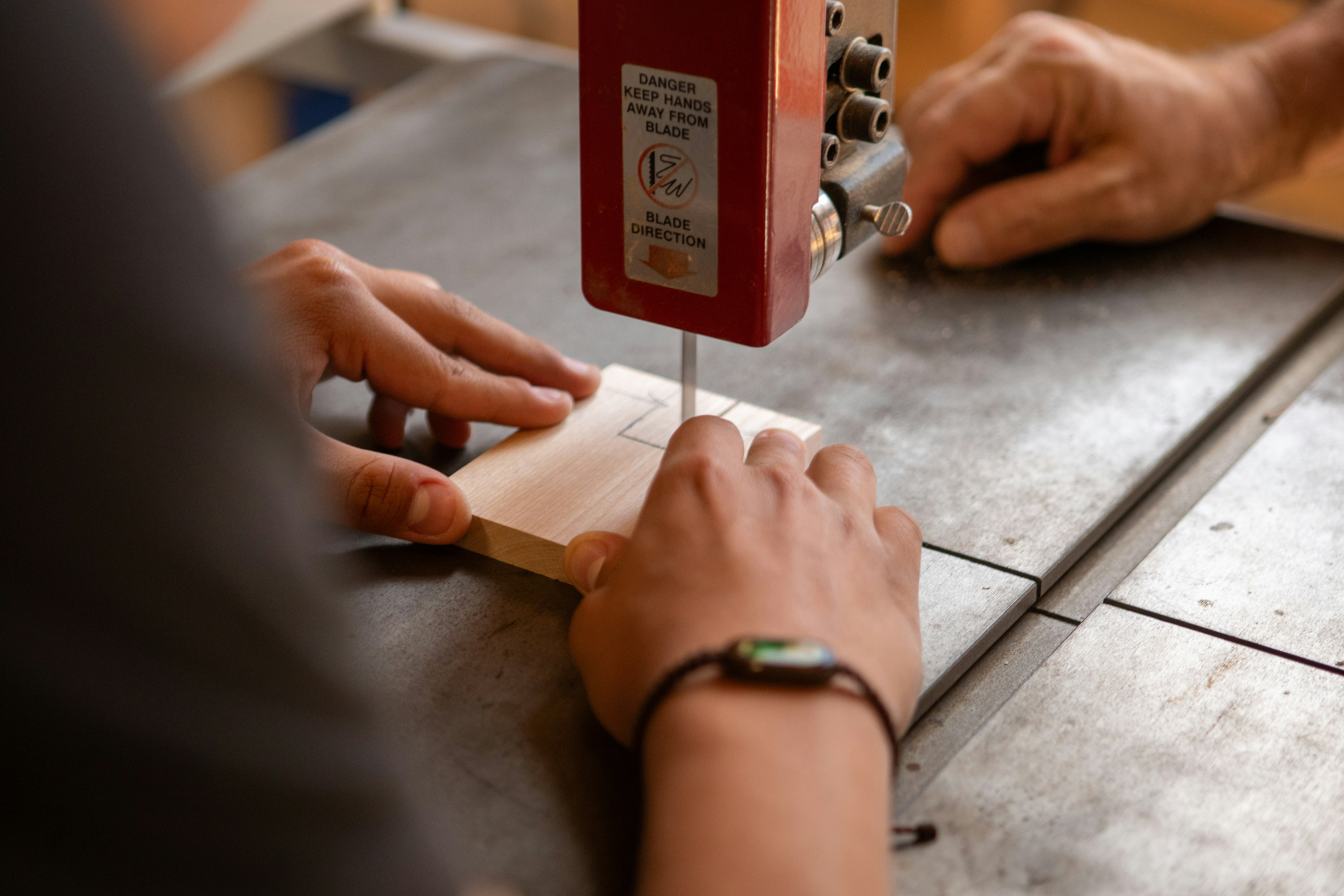 Precision in Woodworking: Hands Guiding a Bandsaw Cut