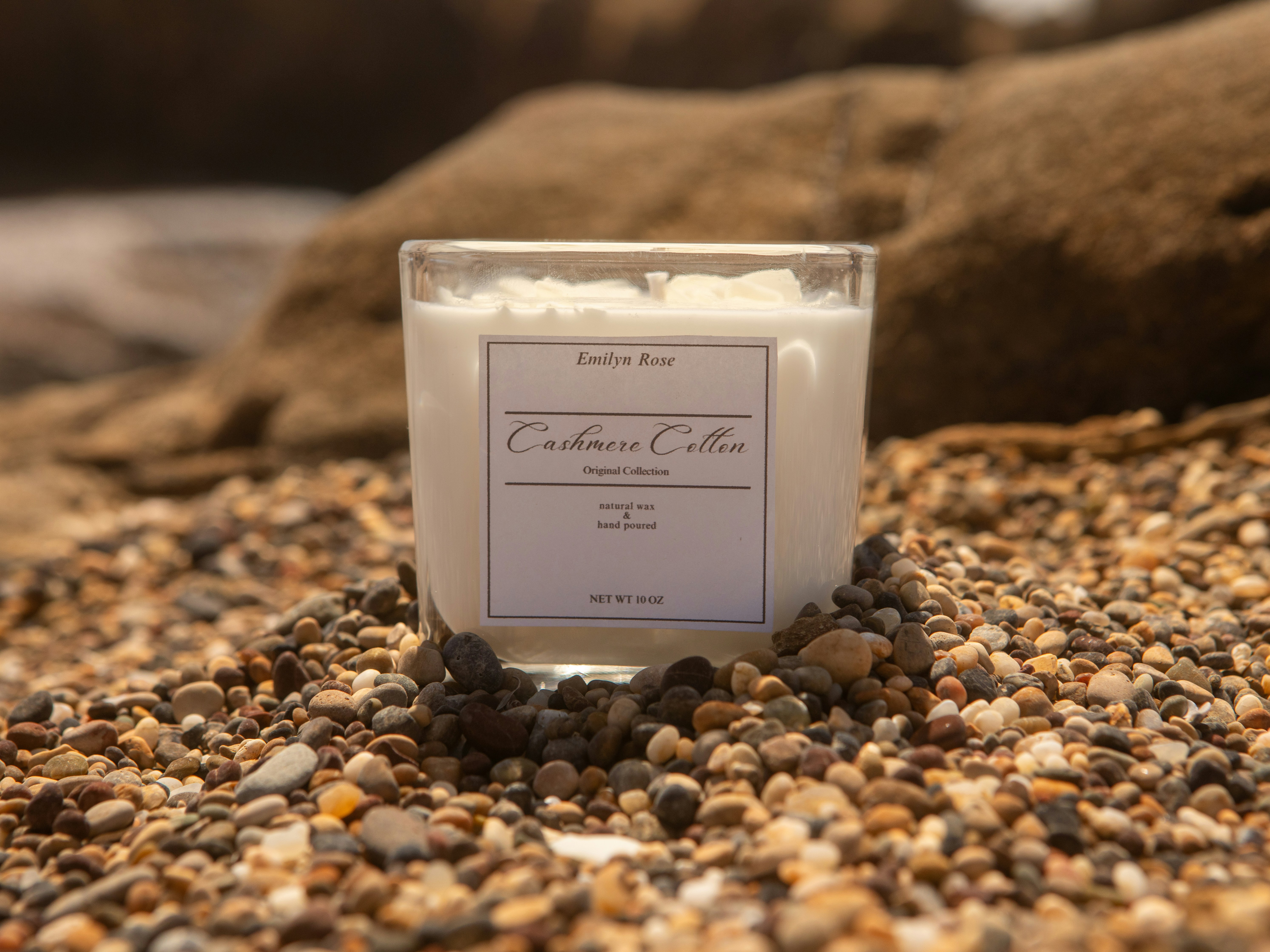 Candle placed on a pebble beach with ocean background