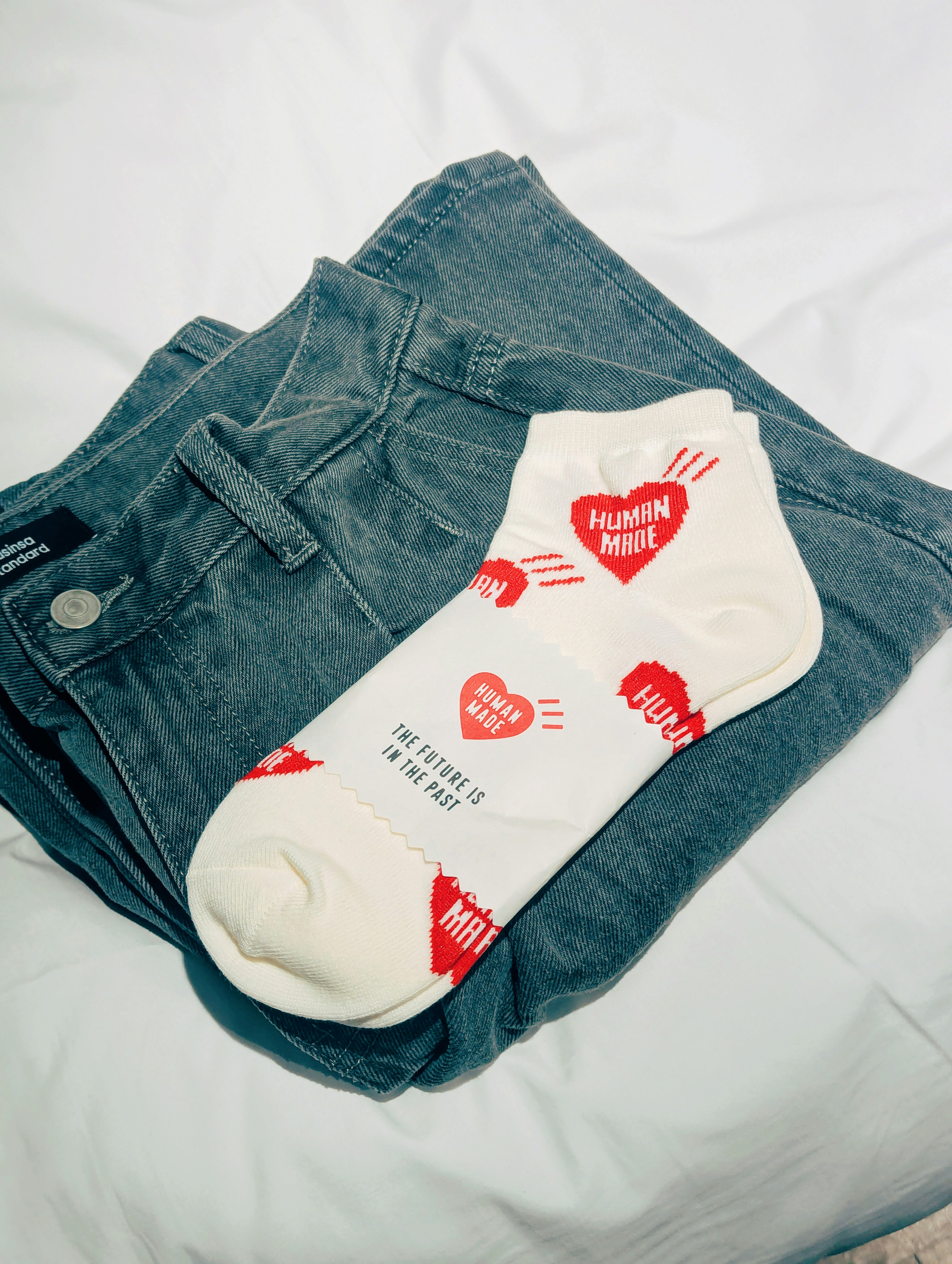 Denim Fold and Cozy Crew: A White Sock with Red Hearts Resting on Jeans