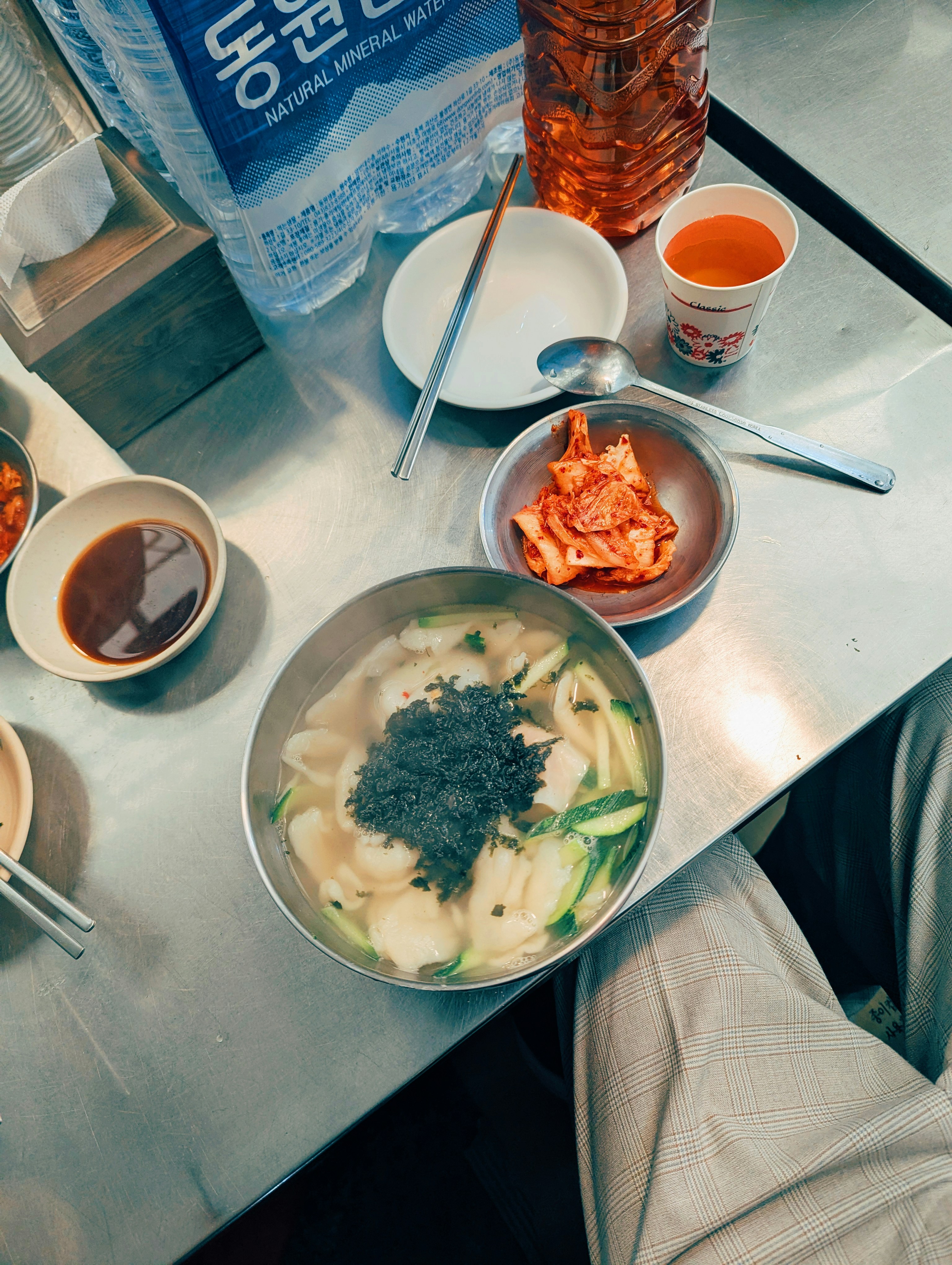 Bowl of dumplings and greens on a metallic table with side dishes