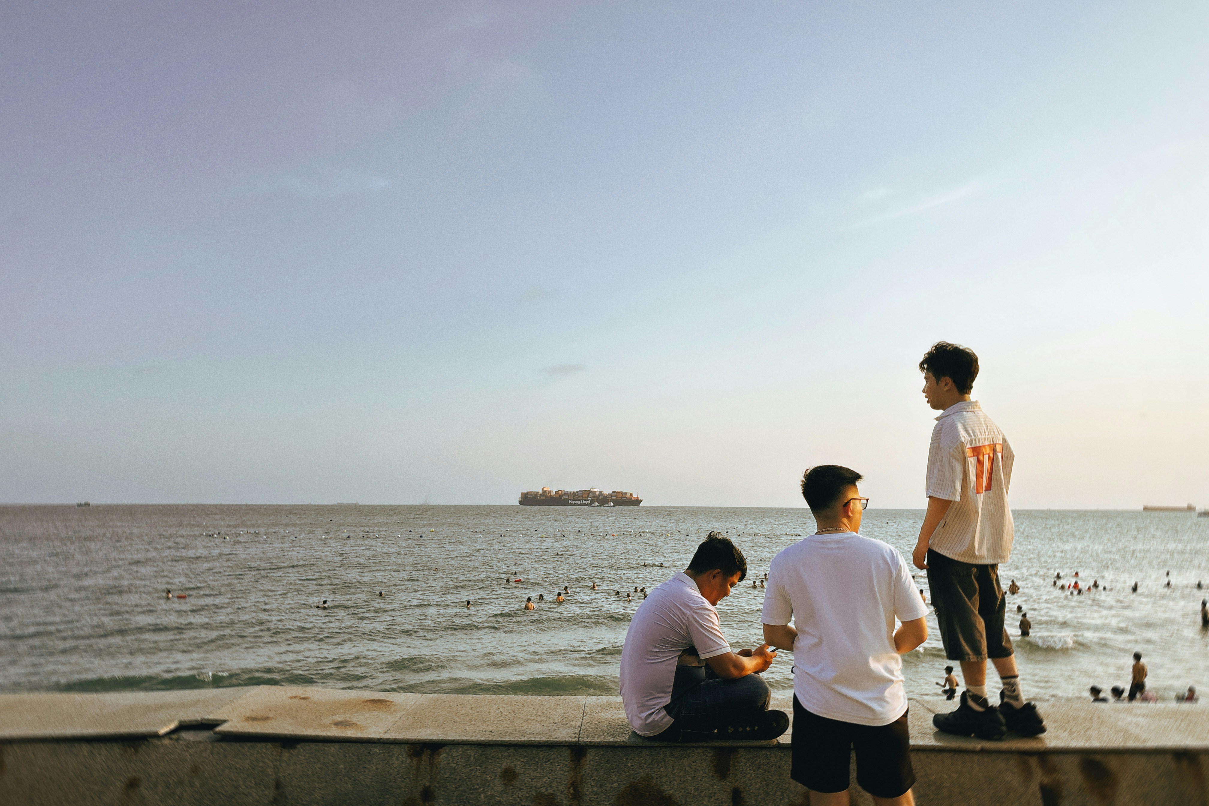 Shoreline Standouts: Friends on the Concrete Pier as Distant Boats Drift by