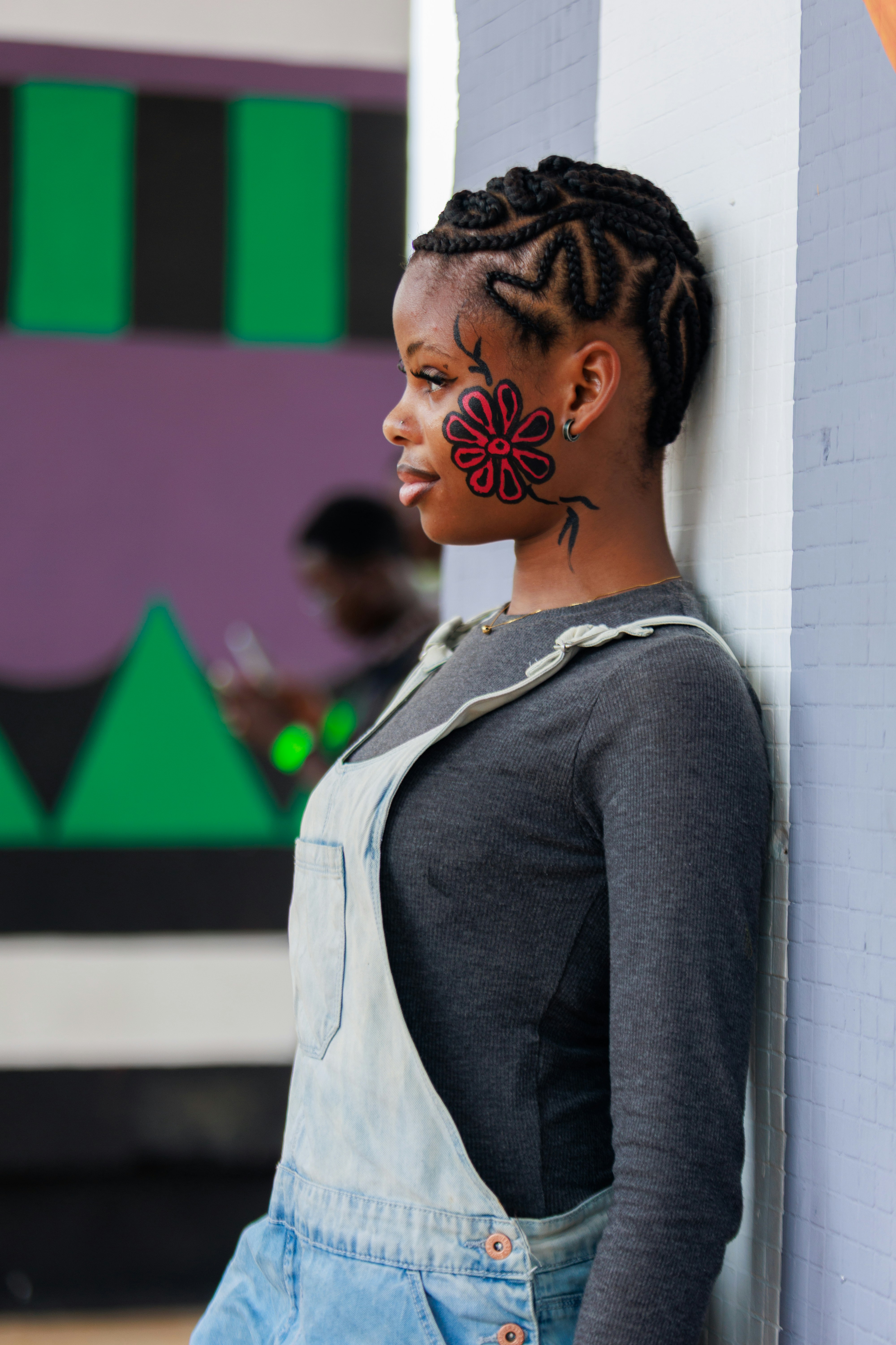 Side Portrait of a Tattooed Artist Leaning Against a Painted Wall