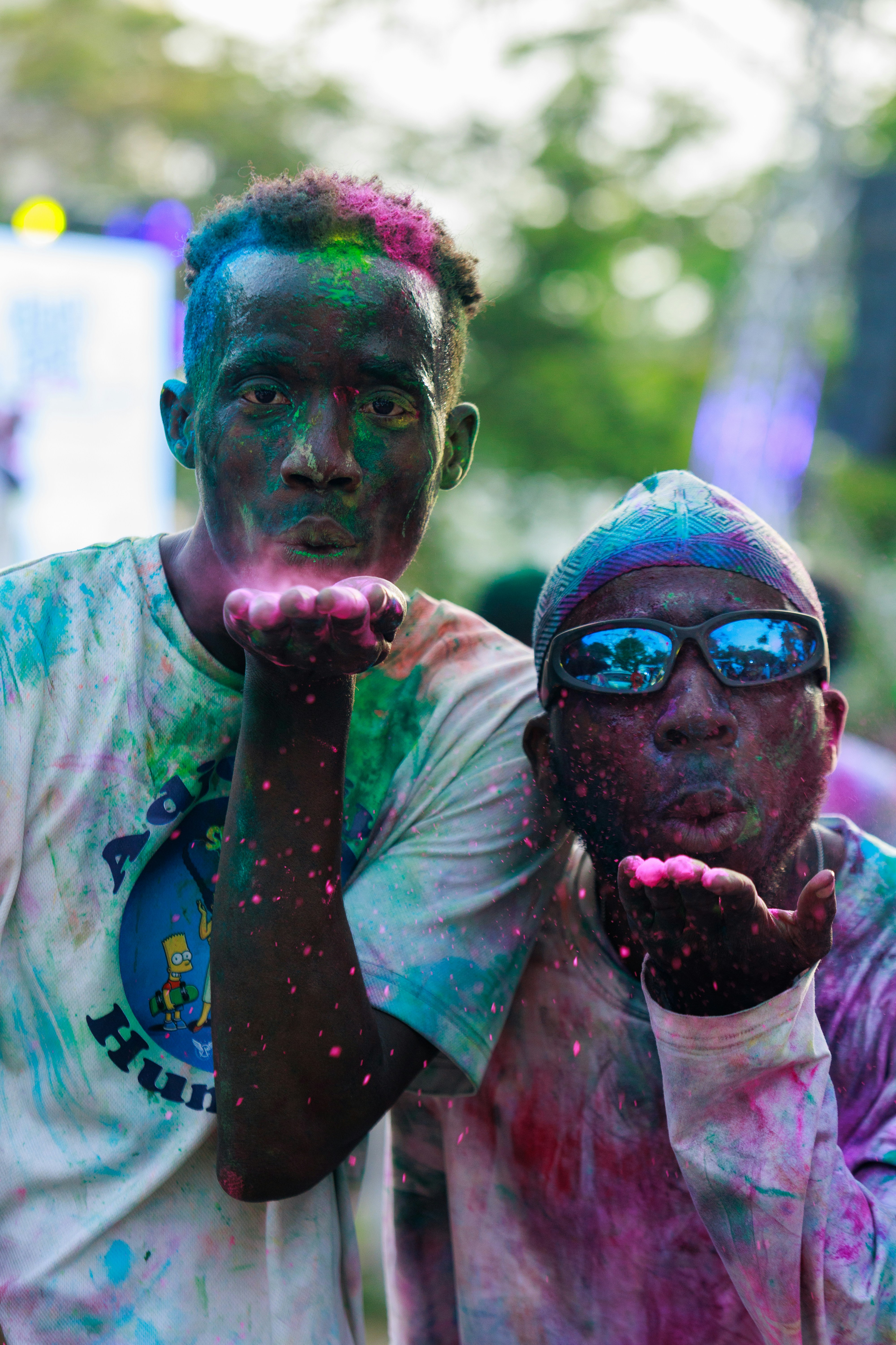Two men blowing colored powder at the camera