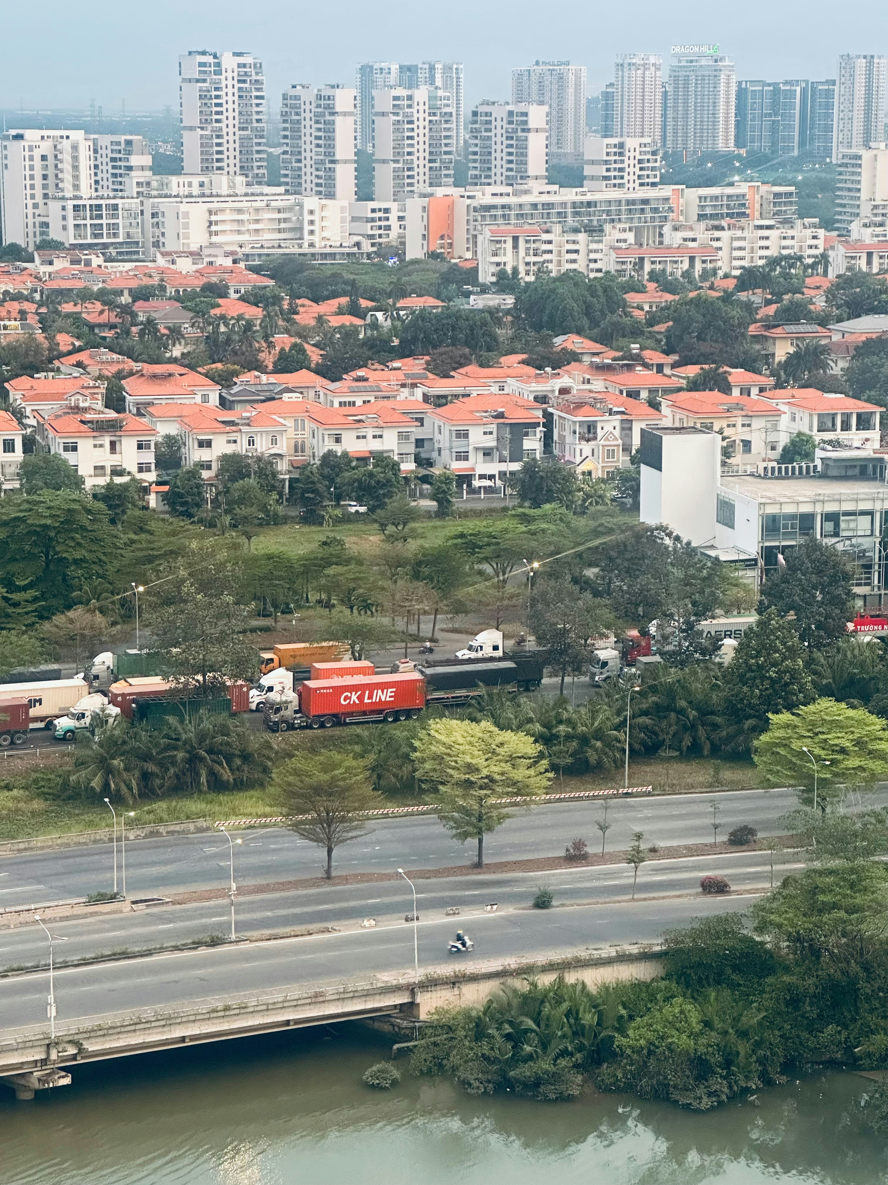 Rush Hour Overpass: Trucks and Terrace Homes Beneath a City Skyline