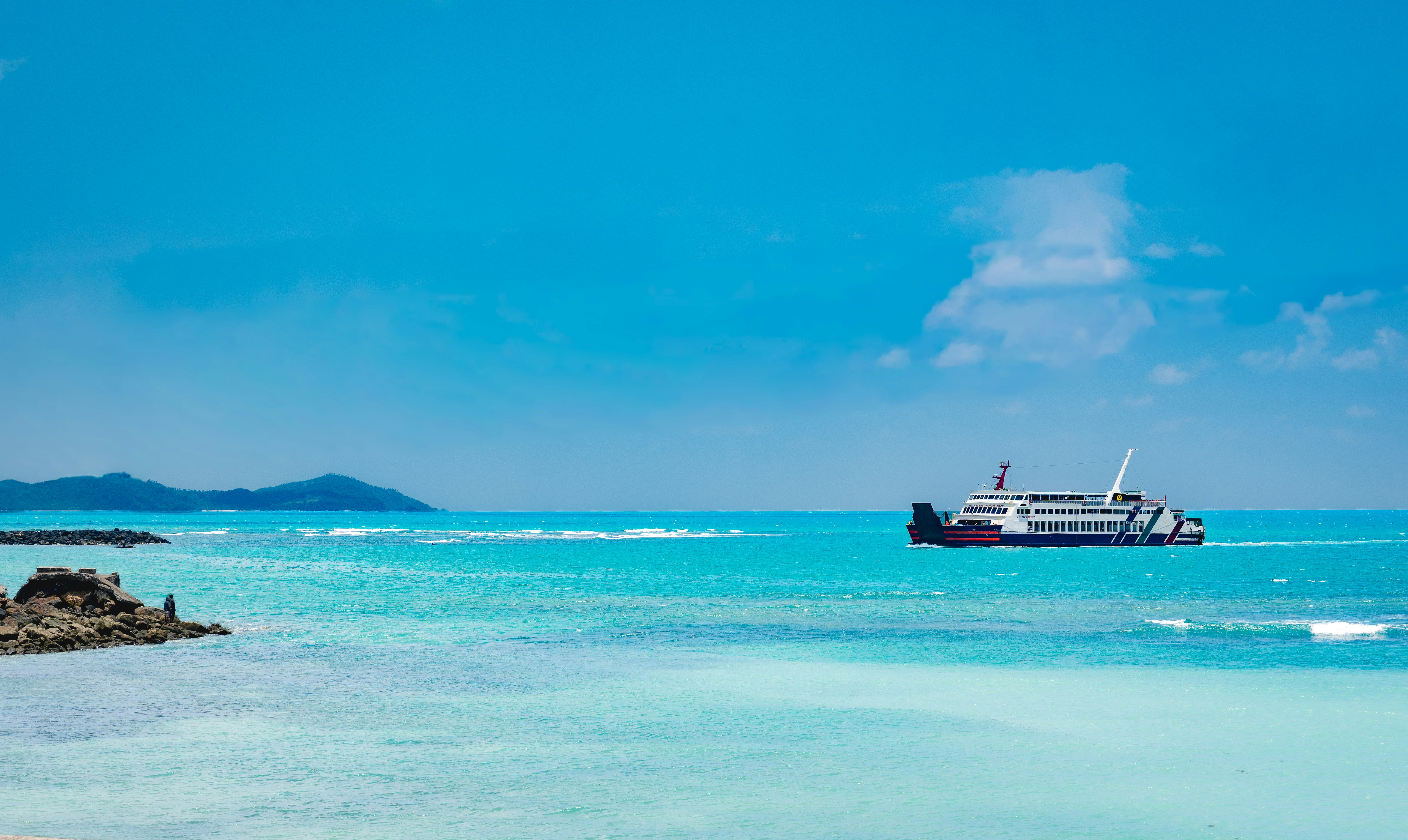 Crossing turquoise seas: a distant ferry on a sunlit horizon