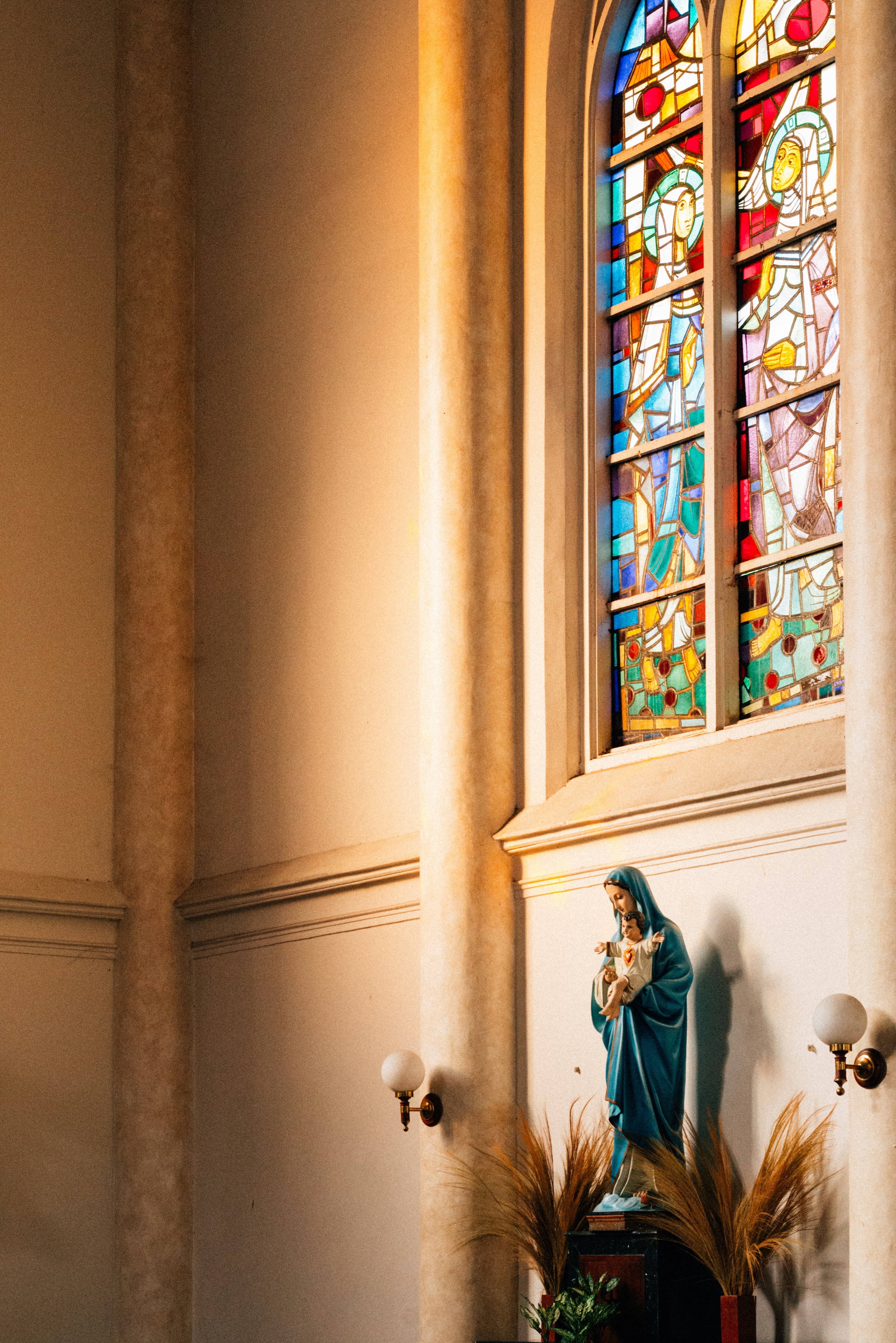 Stained Glass Reverie: A Sacred Statue Beneath Colorful Light
