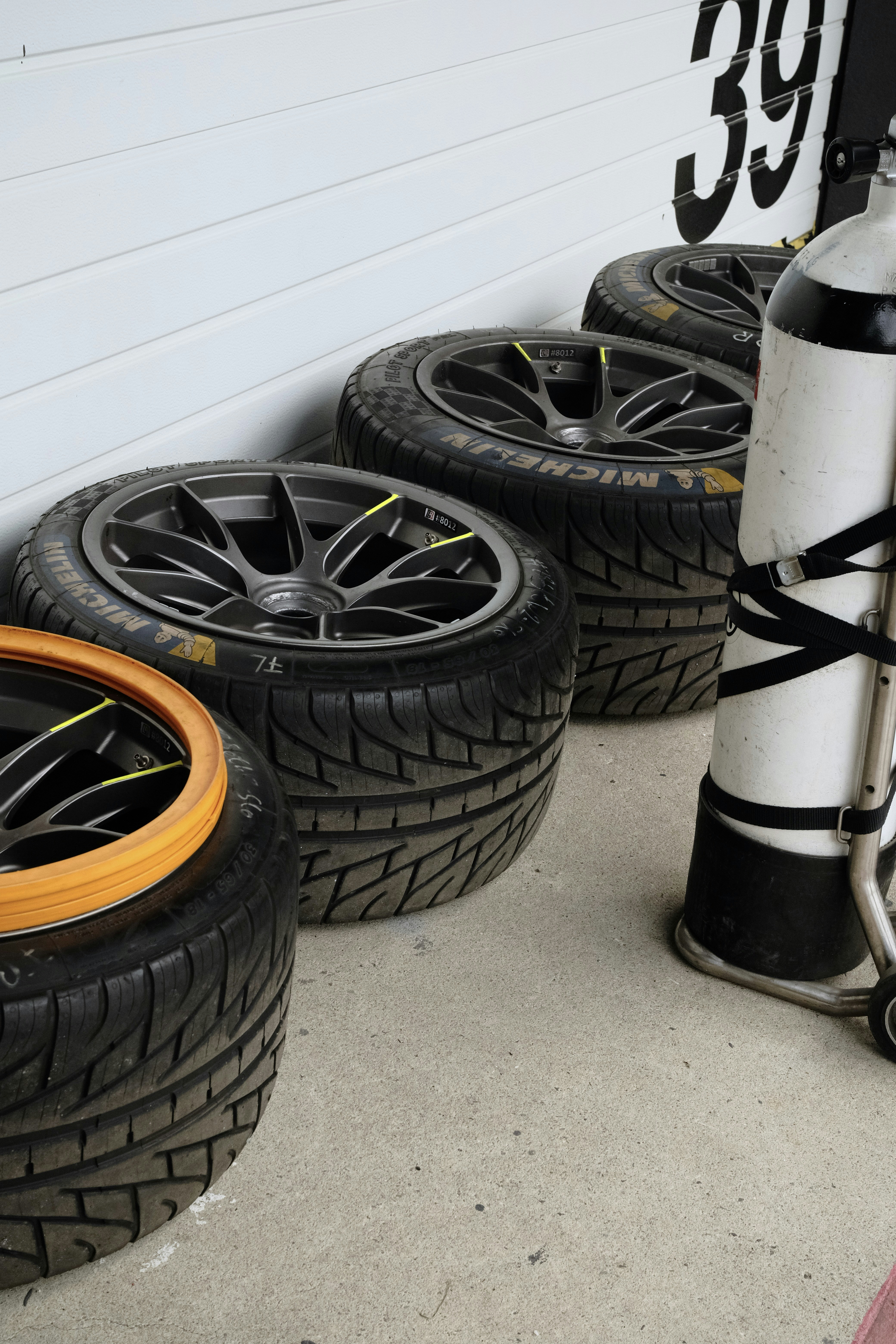 Line of Slick Black Tires Resting Against a White Garage Wall