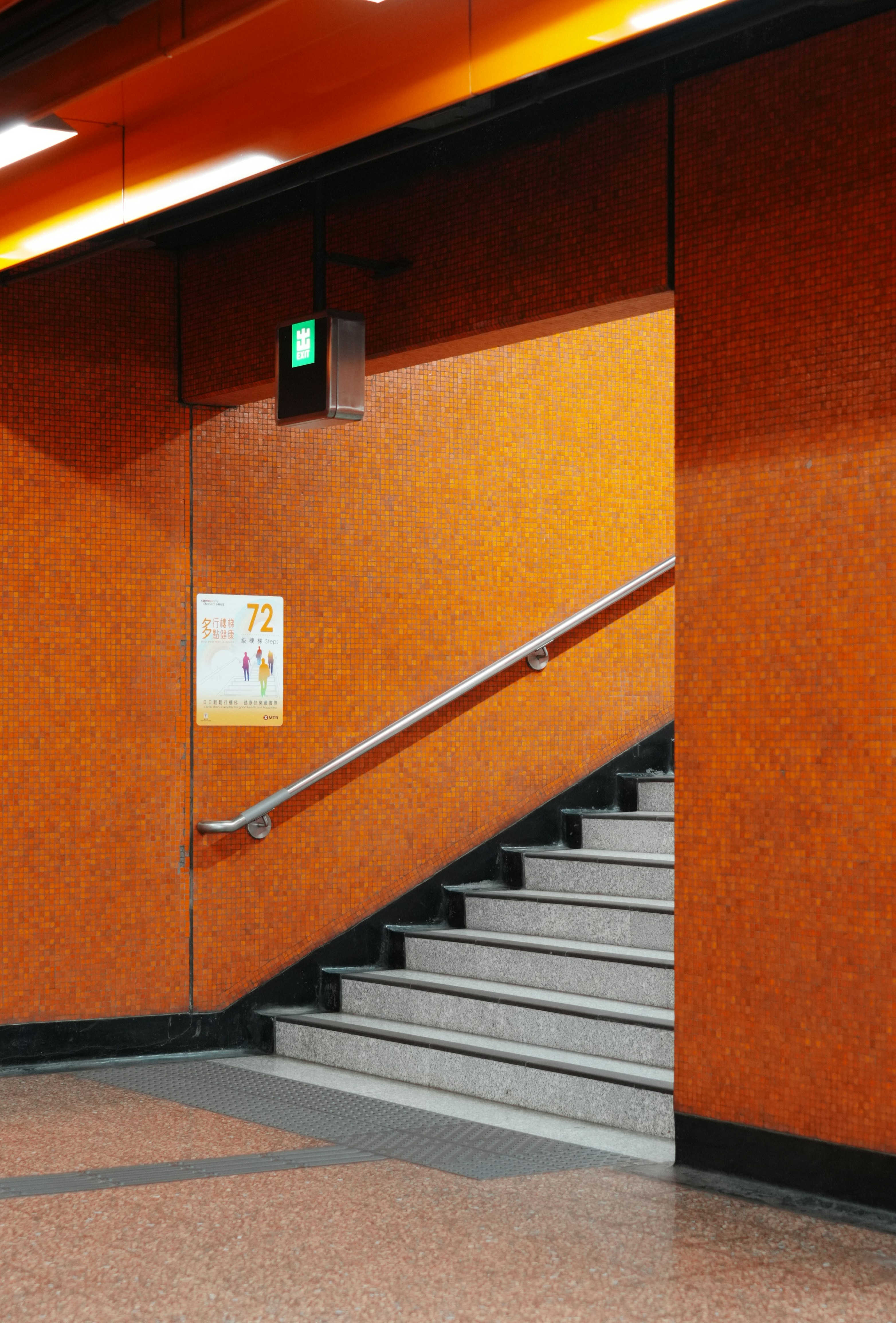 Subway Stairwell Echoes: Orange Walls and Quiet Rail