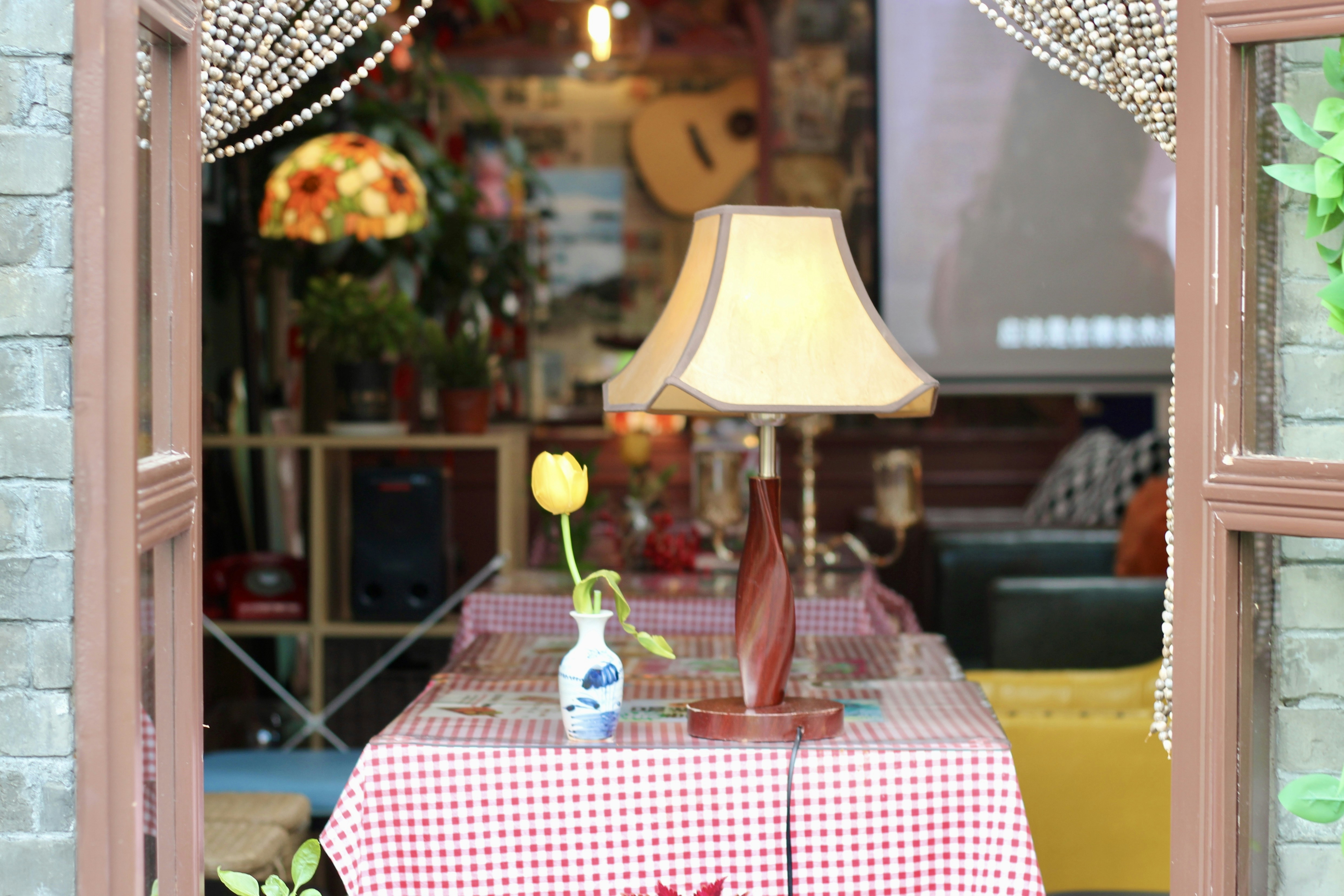 Sunny Bistro Table: A Tulip on a Checkered Tablecloth Under a Cozy Lamp